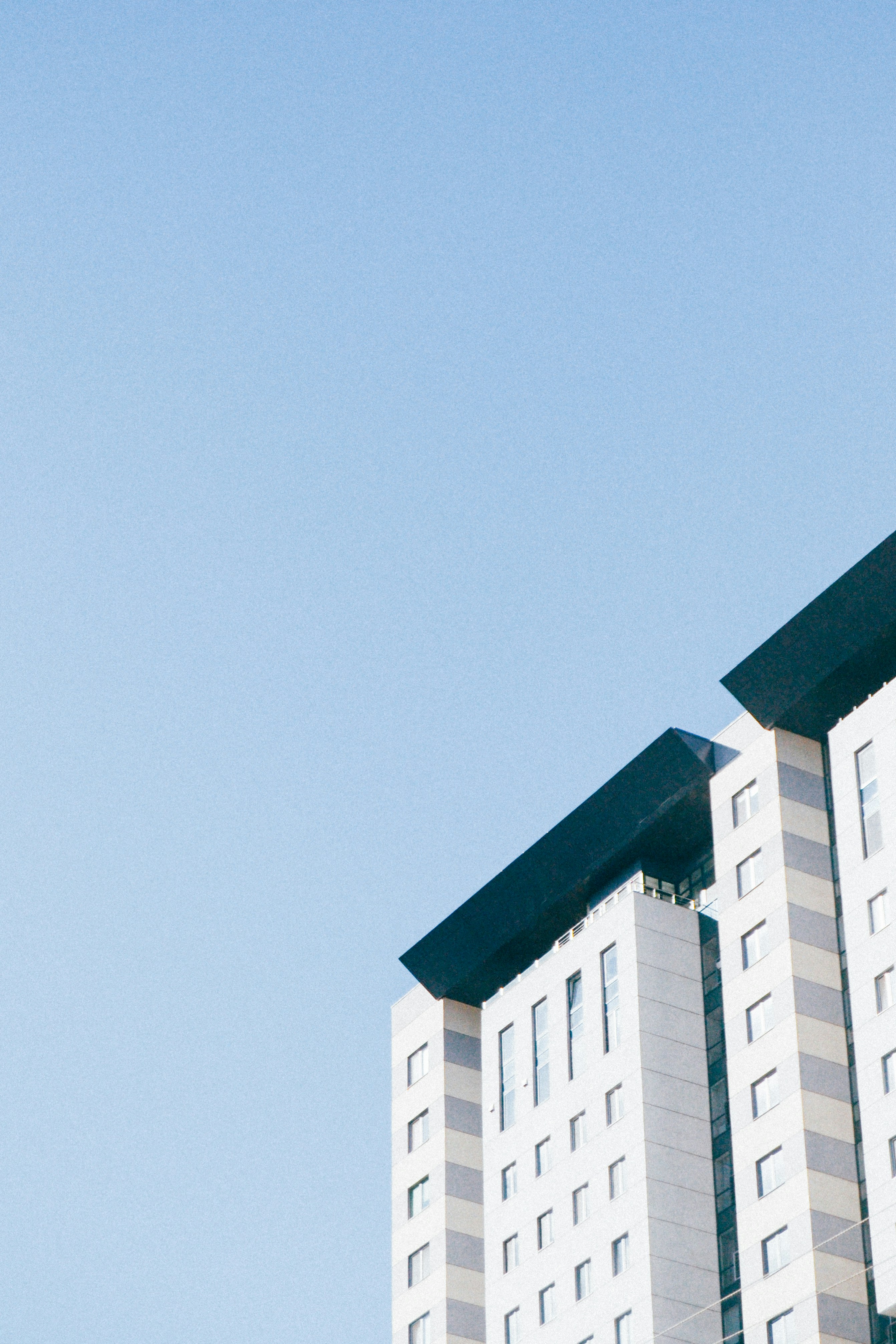 Modern high-rise building with geometric patterns against a clear blue sky.