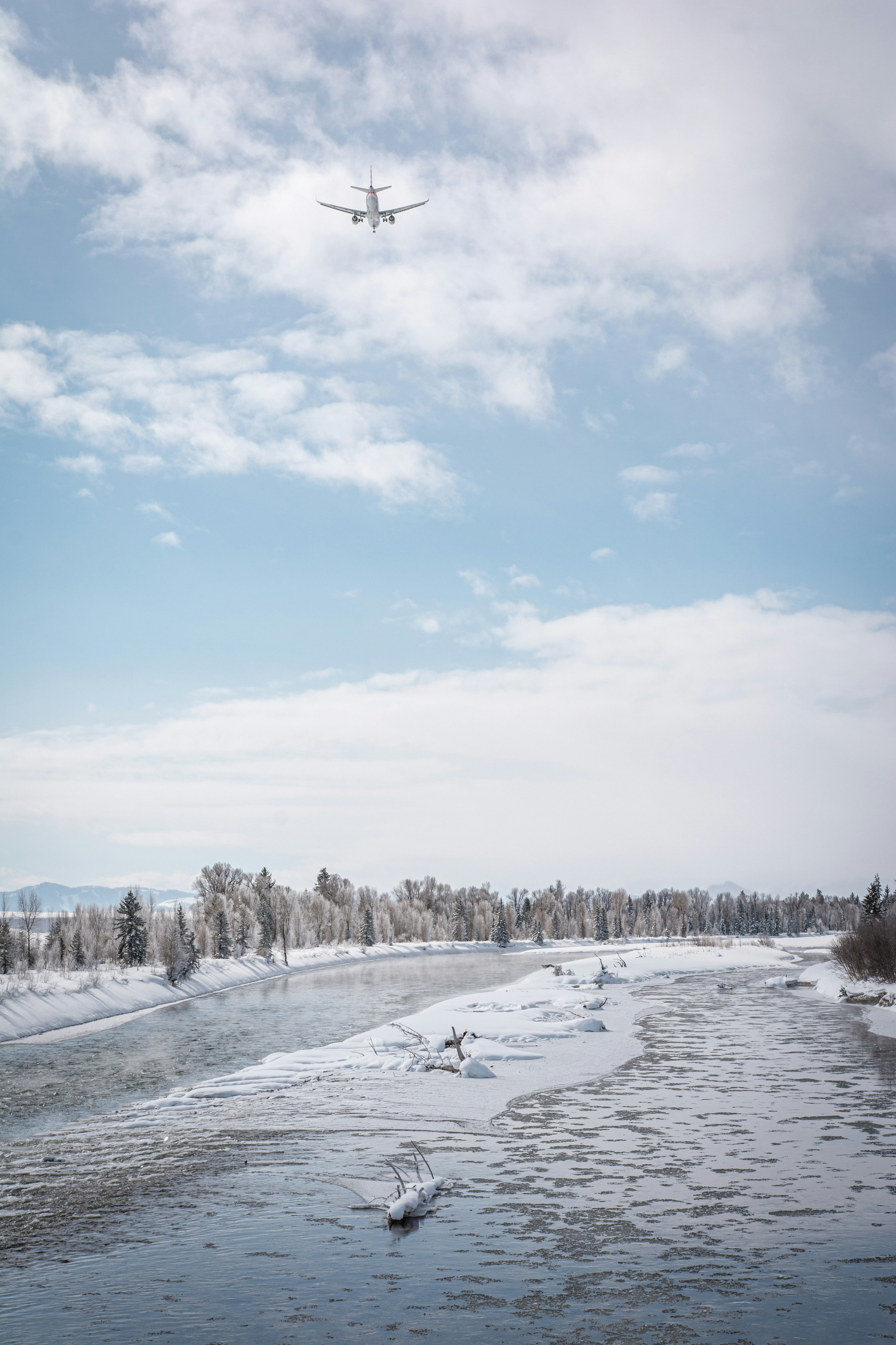 Jet Crossing the Pale Winter Sky Over a Snowbound River Valley