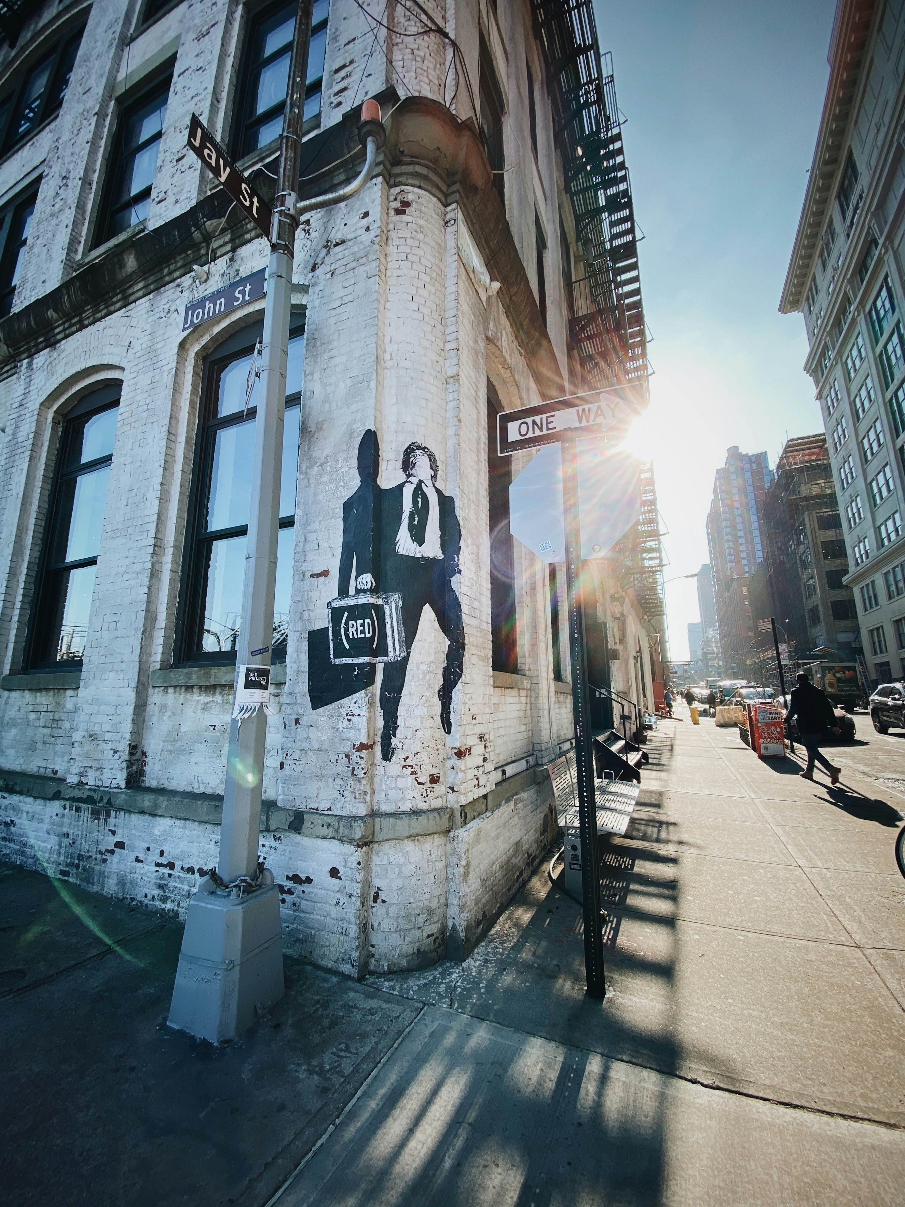 Sunlit Street Corner with Muraled Figure and Echoing Sign