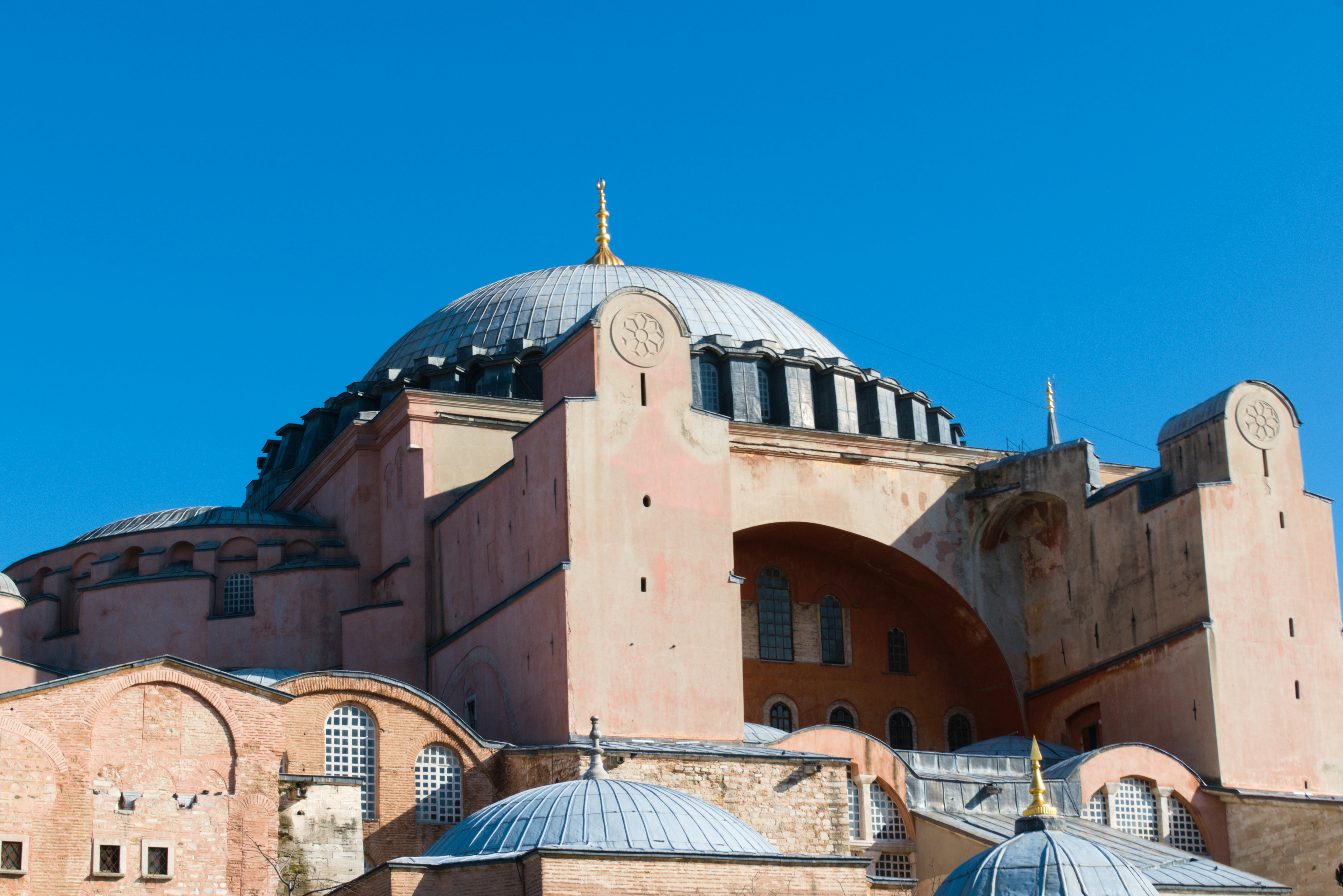 Historic domed structure with reddish-brown walls against a vibrant blue sky.