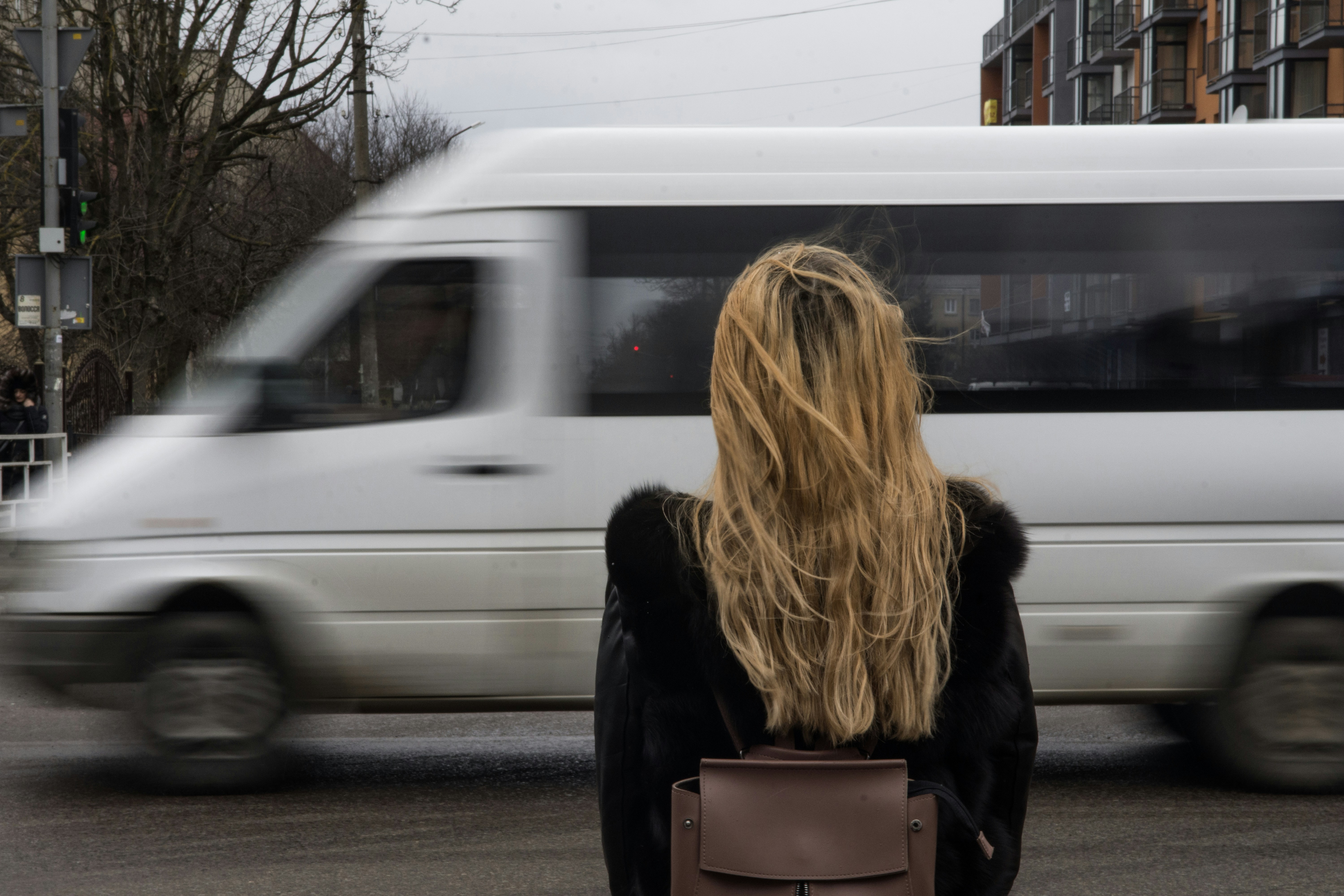 woman in black leather jacket standing beside white van during daytime