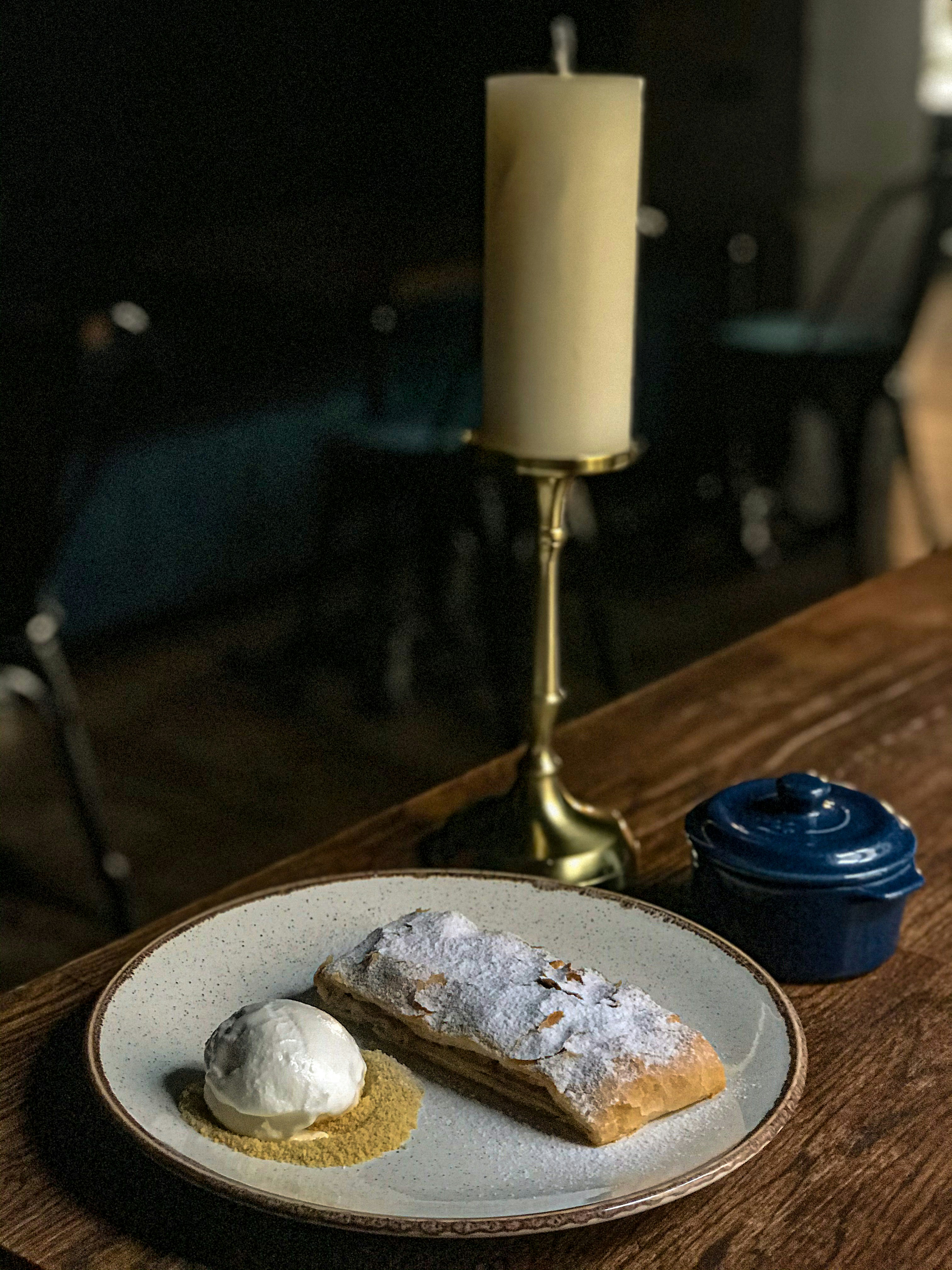 Amber Glow: Powdered Pastry and Vanilla Ice Cream on a Wooden Table