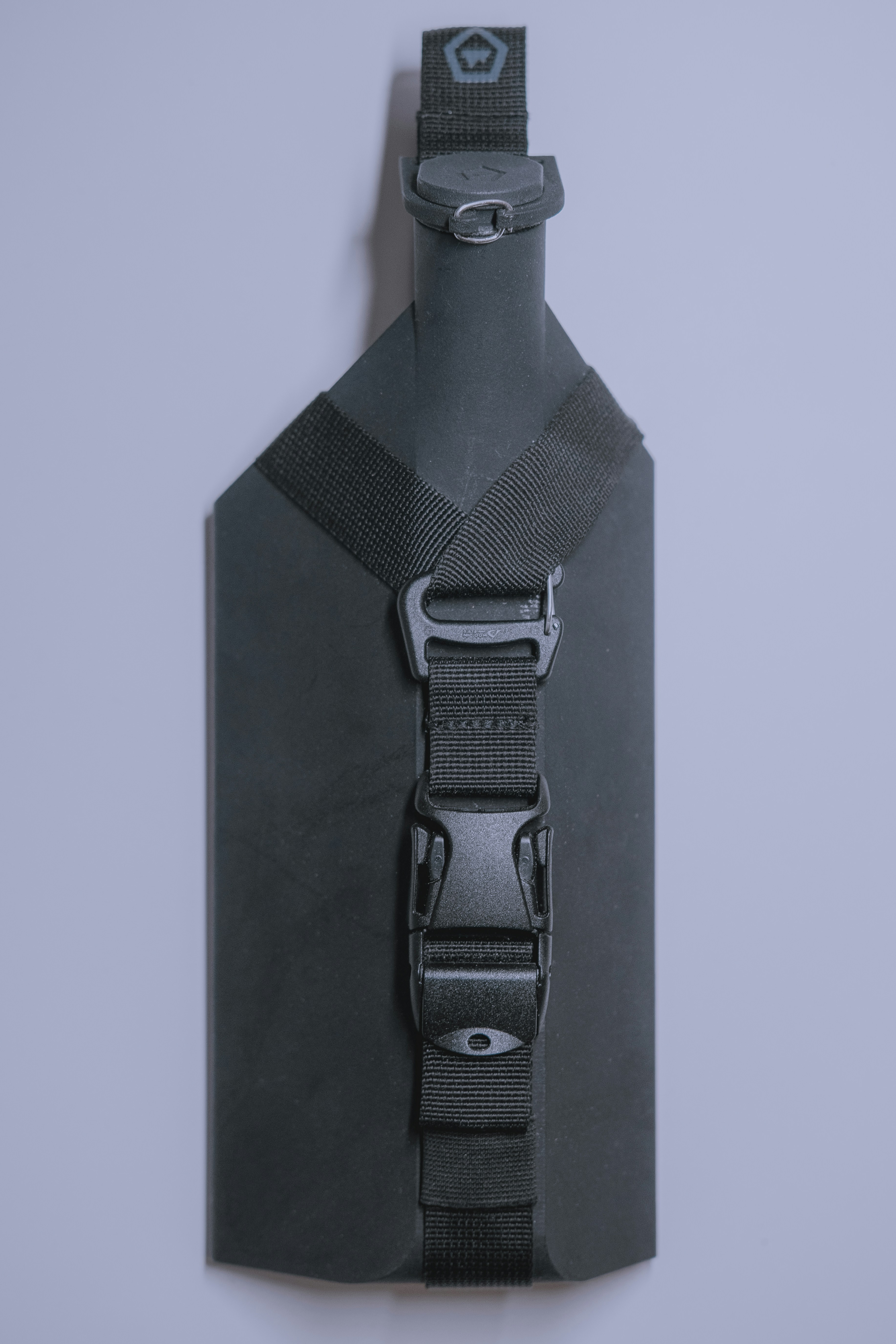 A sleek, black strap system designed for outdoor gear, showcasing its functional elements against a neutral background.
