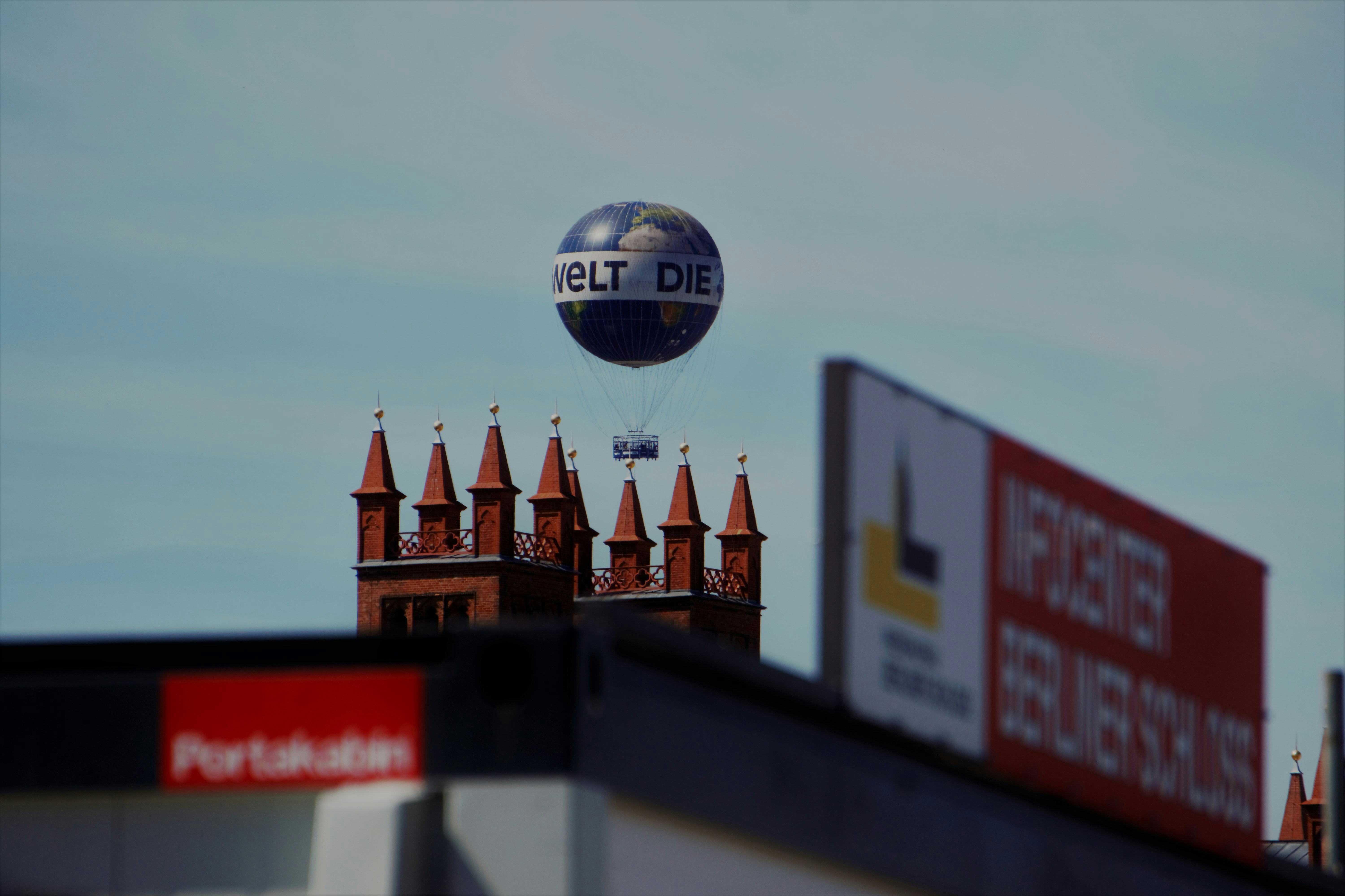Balloon over a historic rooftop: a playful tether above red-brick turrets