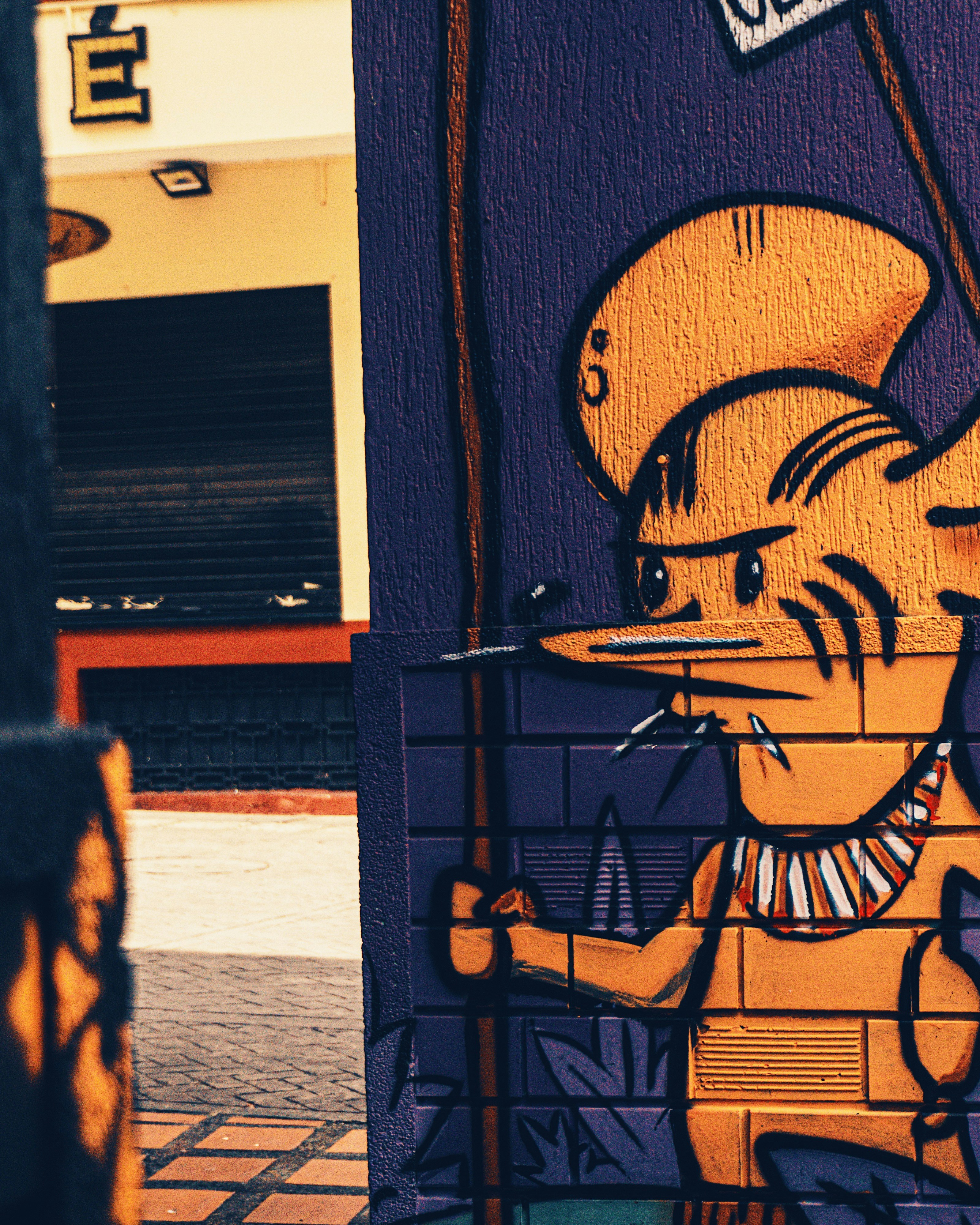 Urban mural with bold cartoon character peeking from a doorway