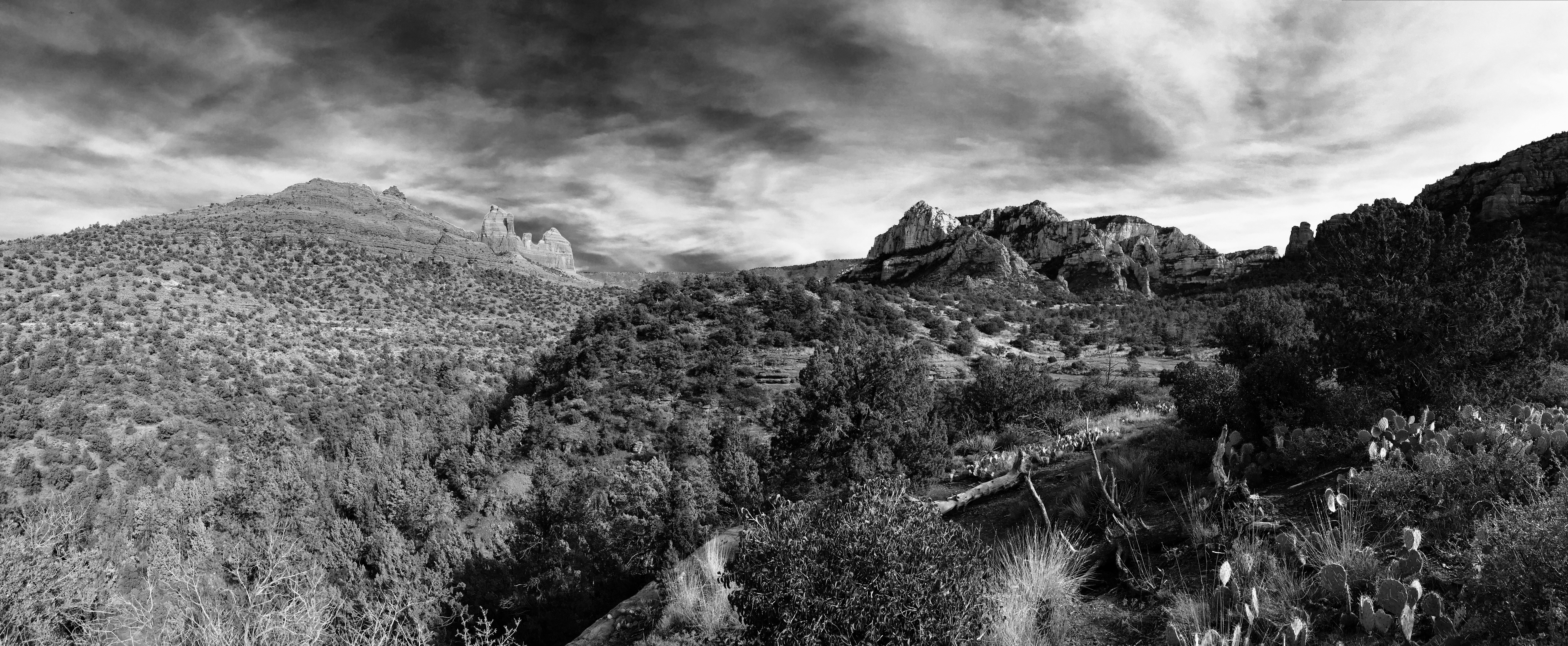 A panoramic view of a rugged desert landscape, showcasing dramatic rock formations and a sprawling terrain under a moody sky.