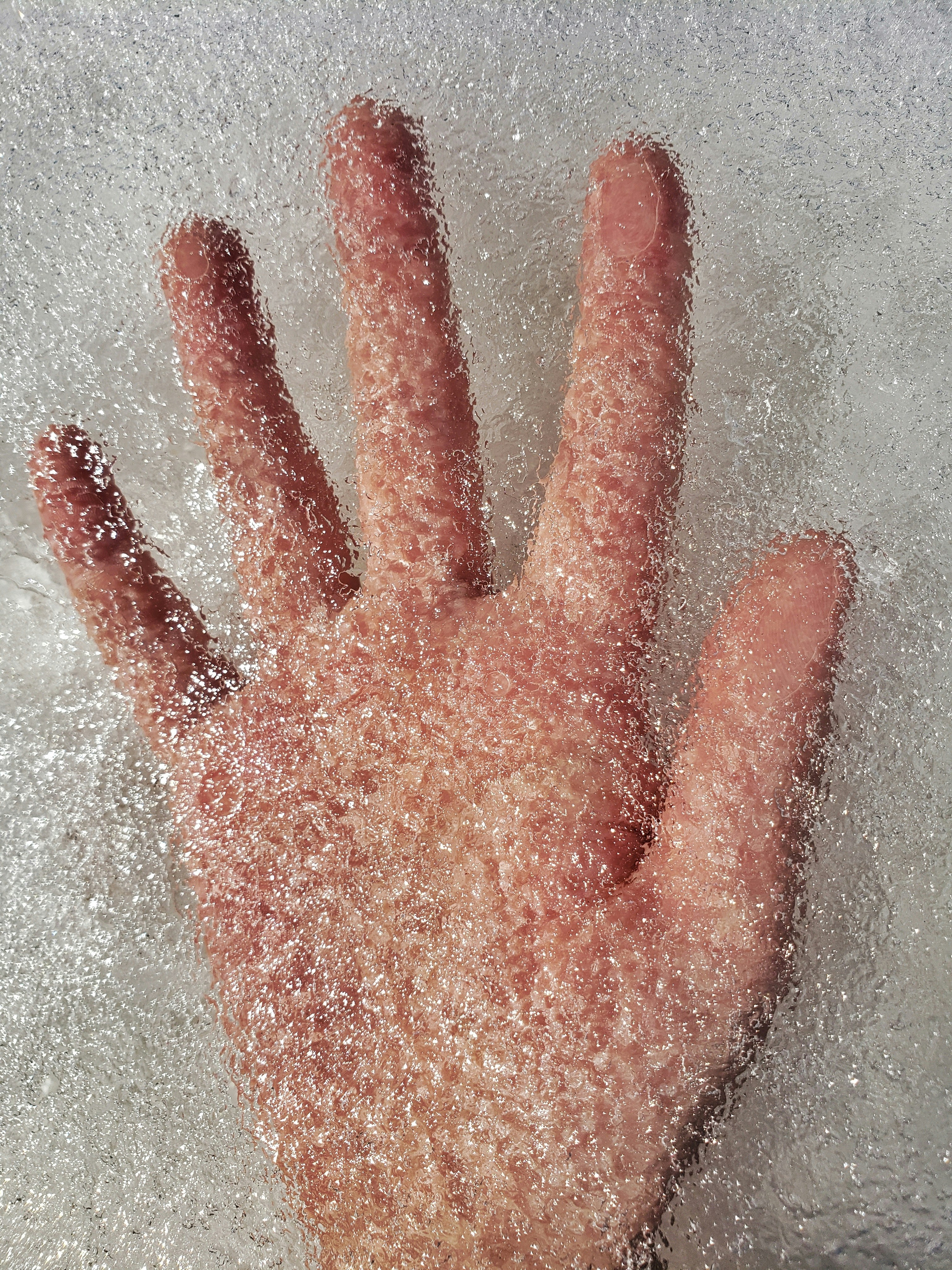 Sugar-dusted hand pressed against icy glass