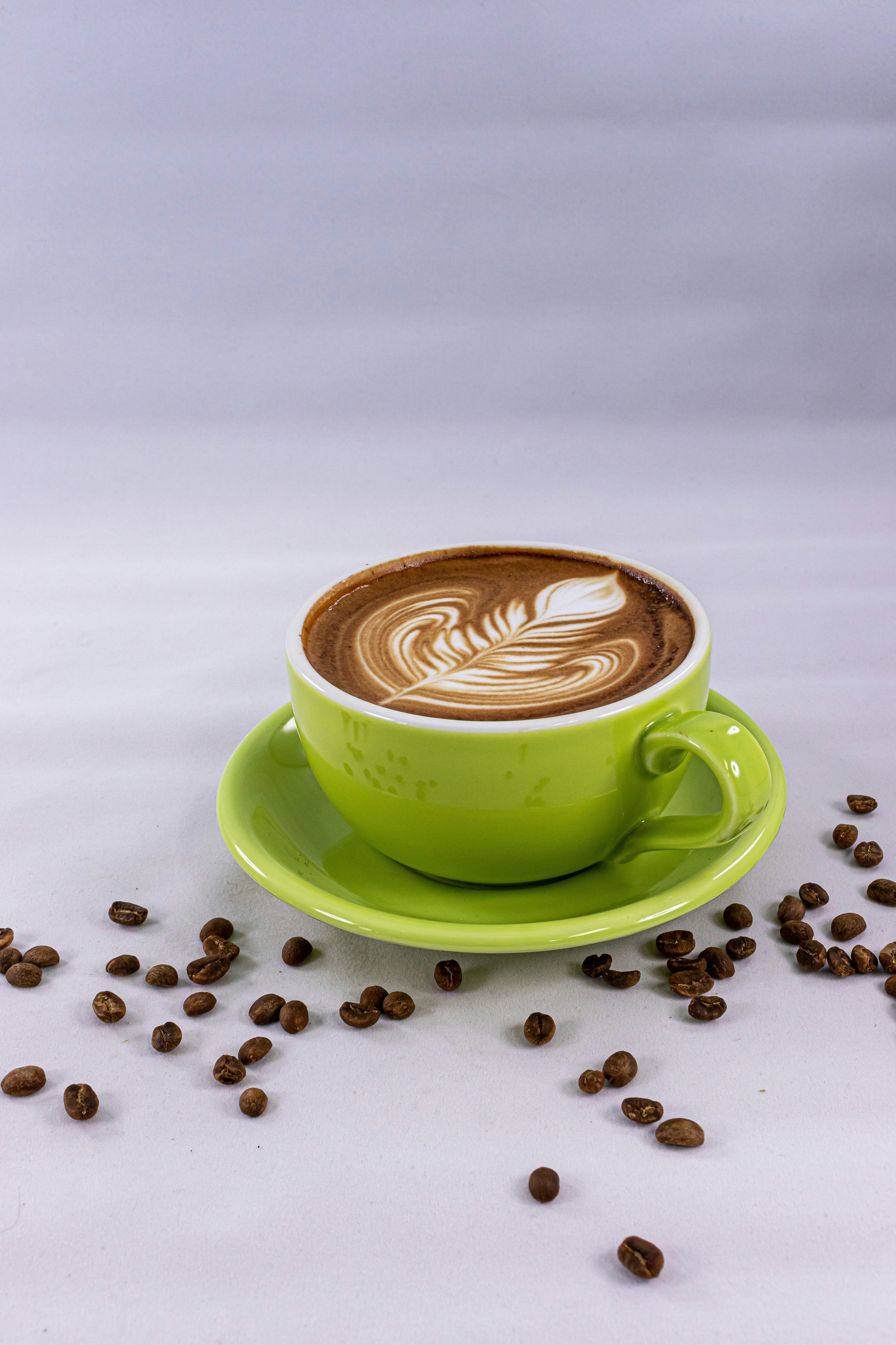 Cafe latte drawing wing-leaf with green cup. pilt light roasted coffee beans(portrait layout) 