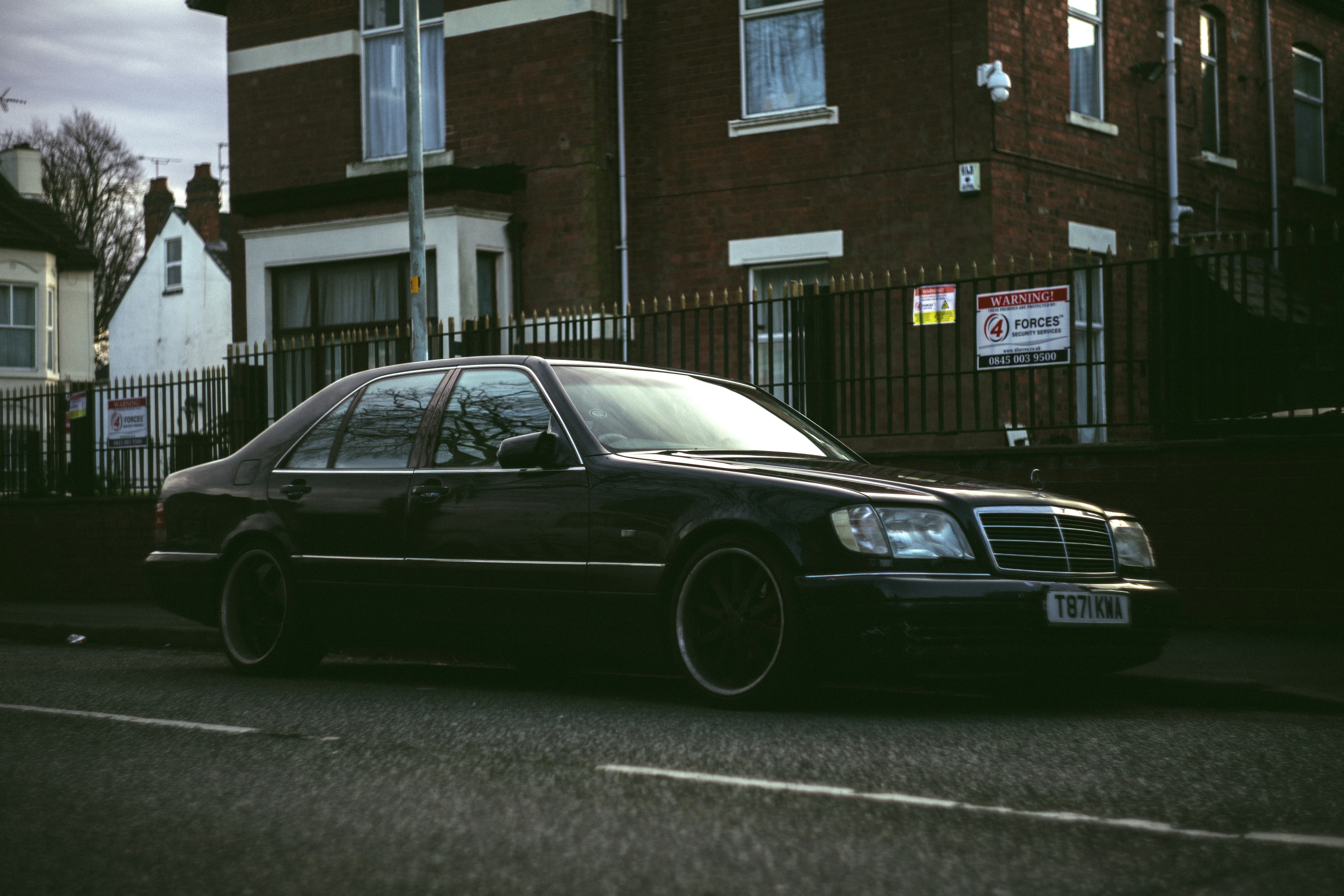 Noir Stance: Black Mercedes Resting on a Brick Street