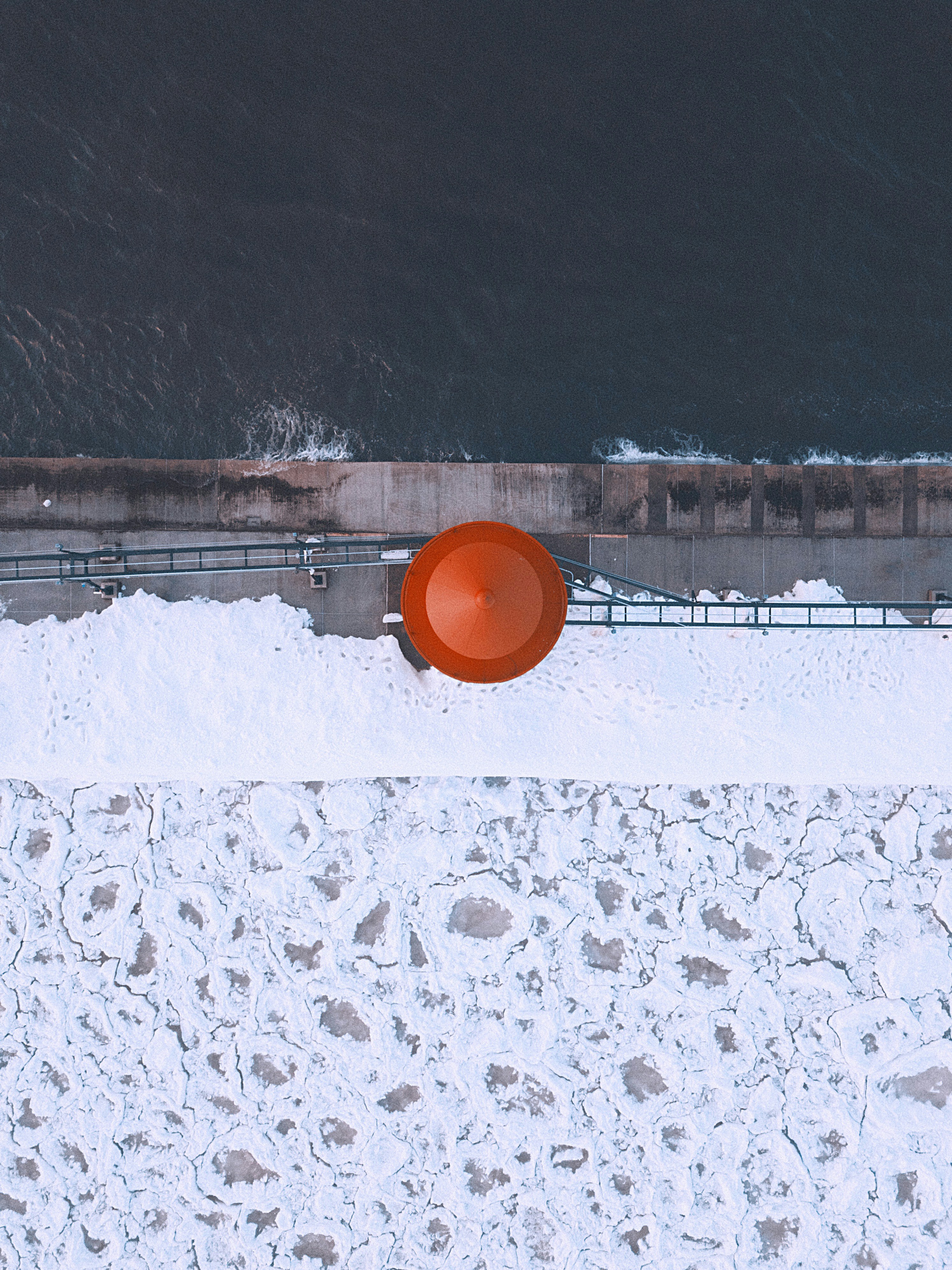 A large orange frisbee sitting on top of snow covered ground photo ...