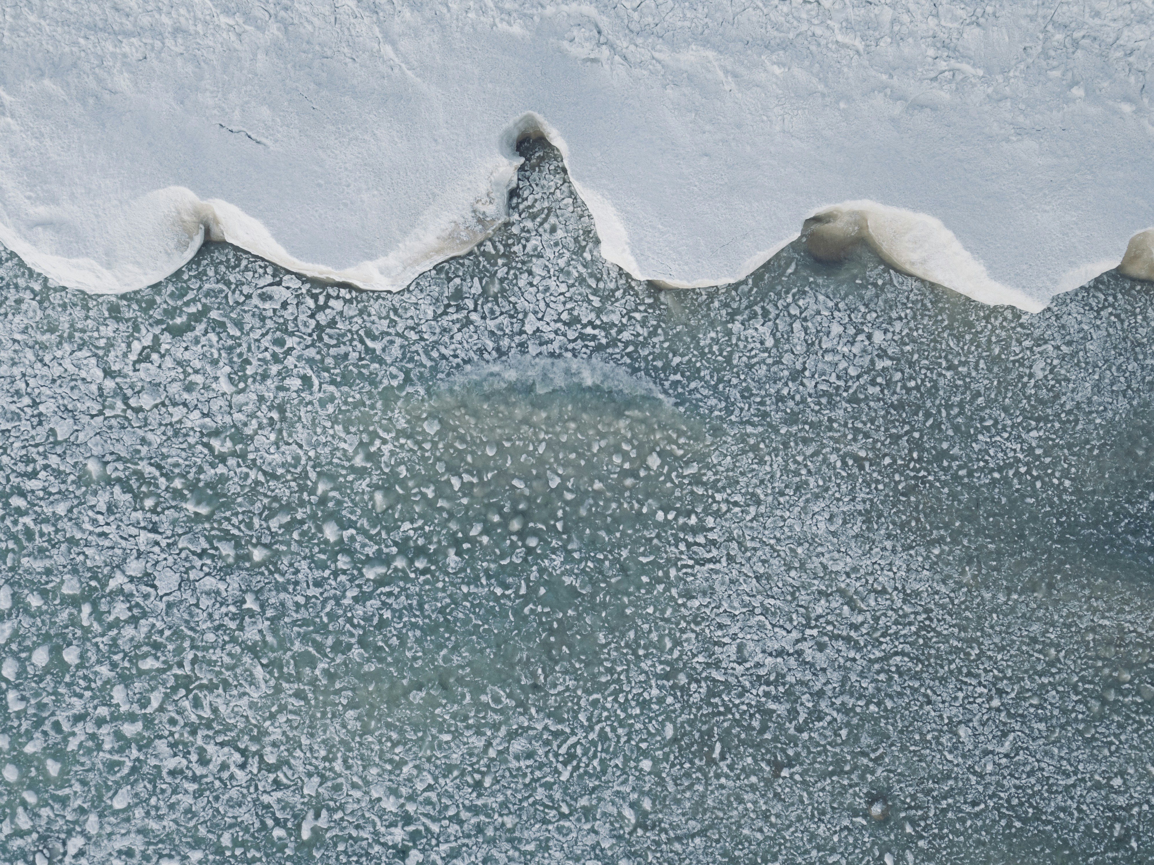 Intricate patterns of ice and water create a textured landscape, showcasing the dynamic interplay between solid and liquid forms.