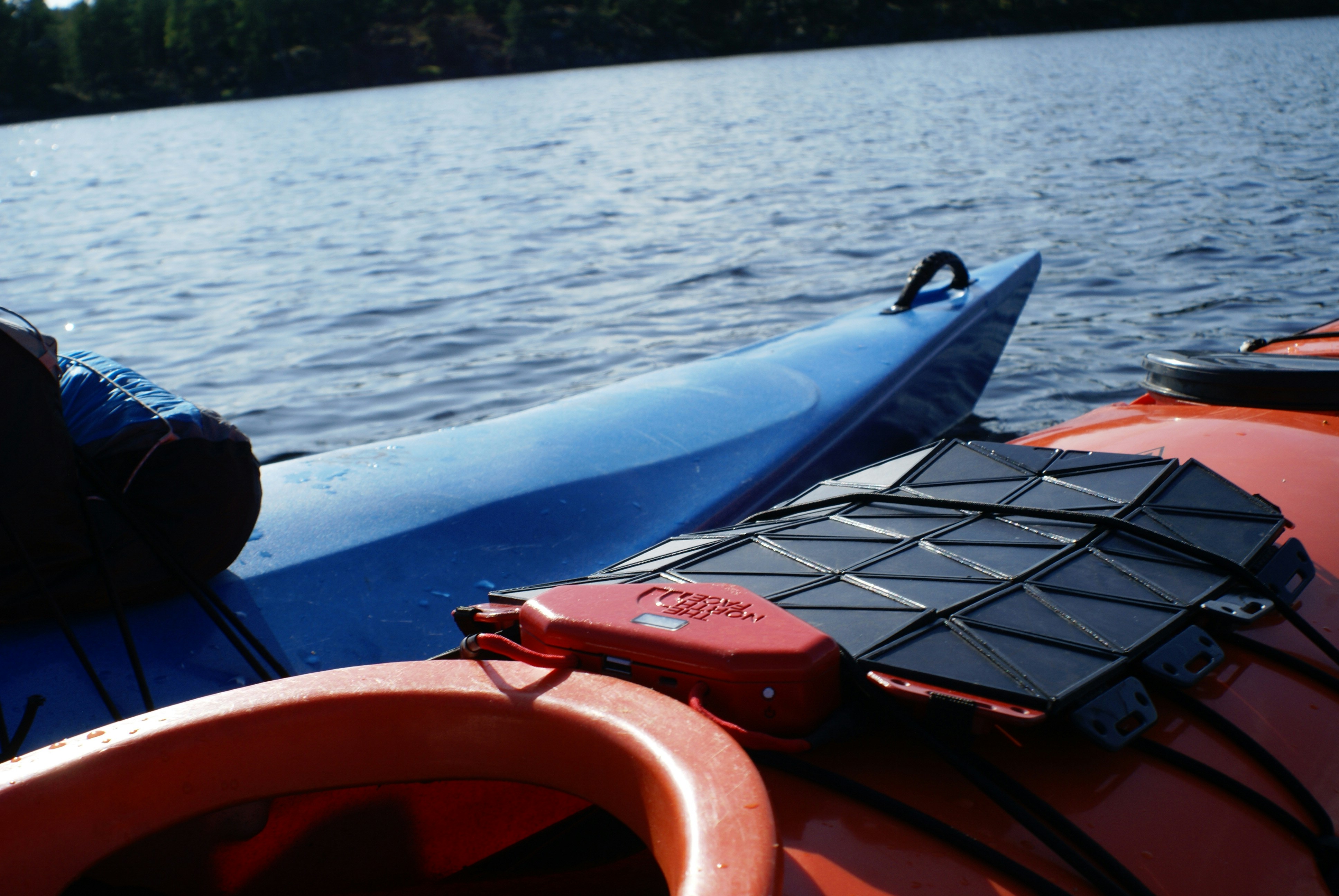 Close-up view of two kayaks on a tranquil lake, showcasing the vibrant colors and textures of the boats and the calm water surface.