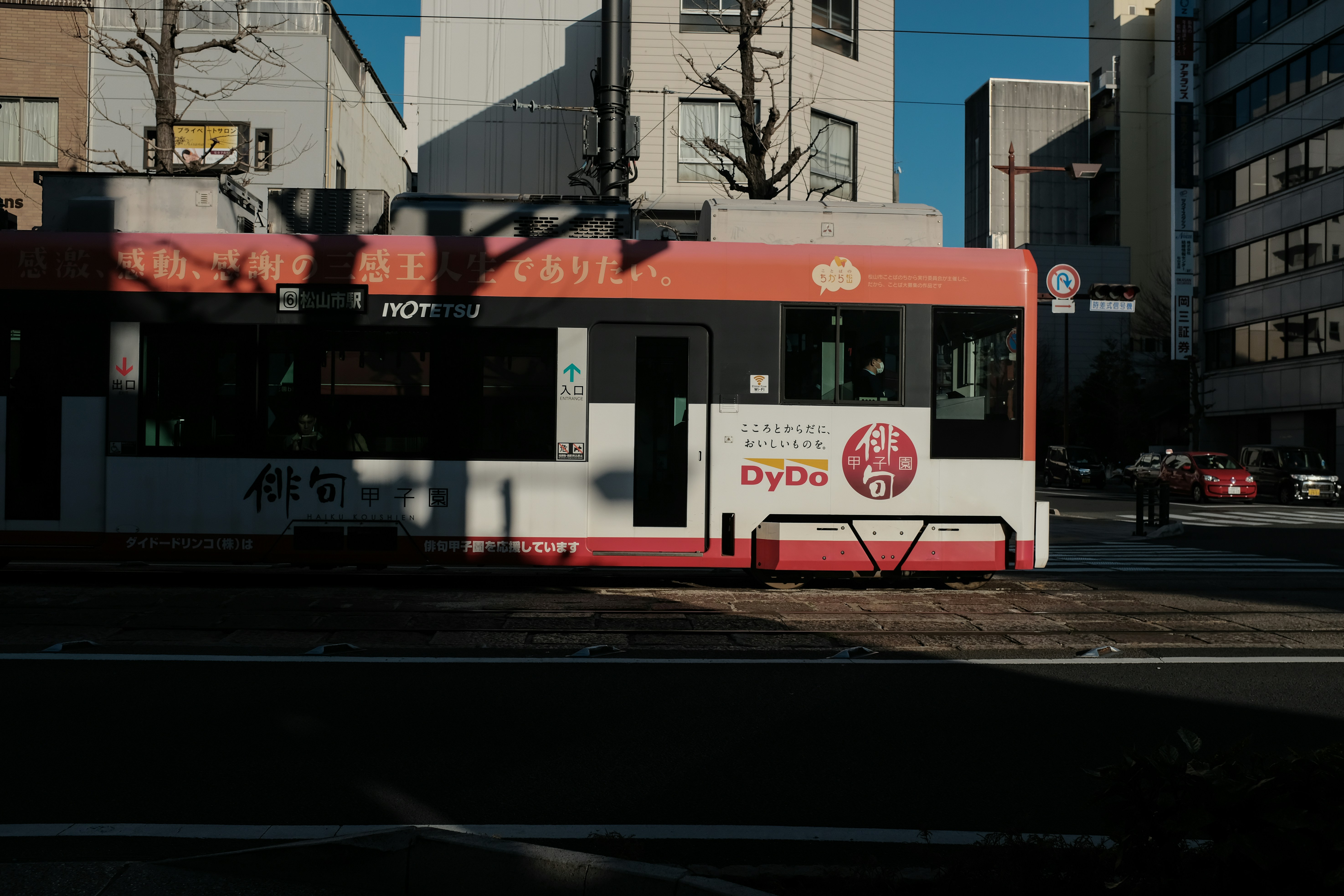 Tram navigating through a city intersection, showcasing vibrant branding against a backdrop of urban architecture.