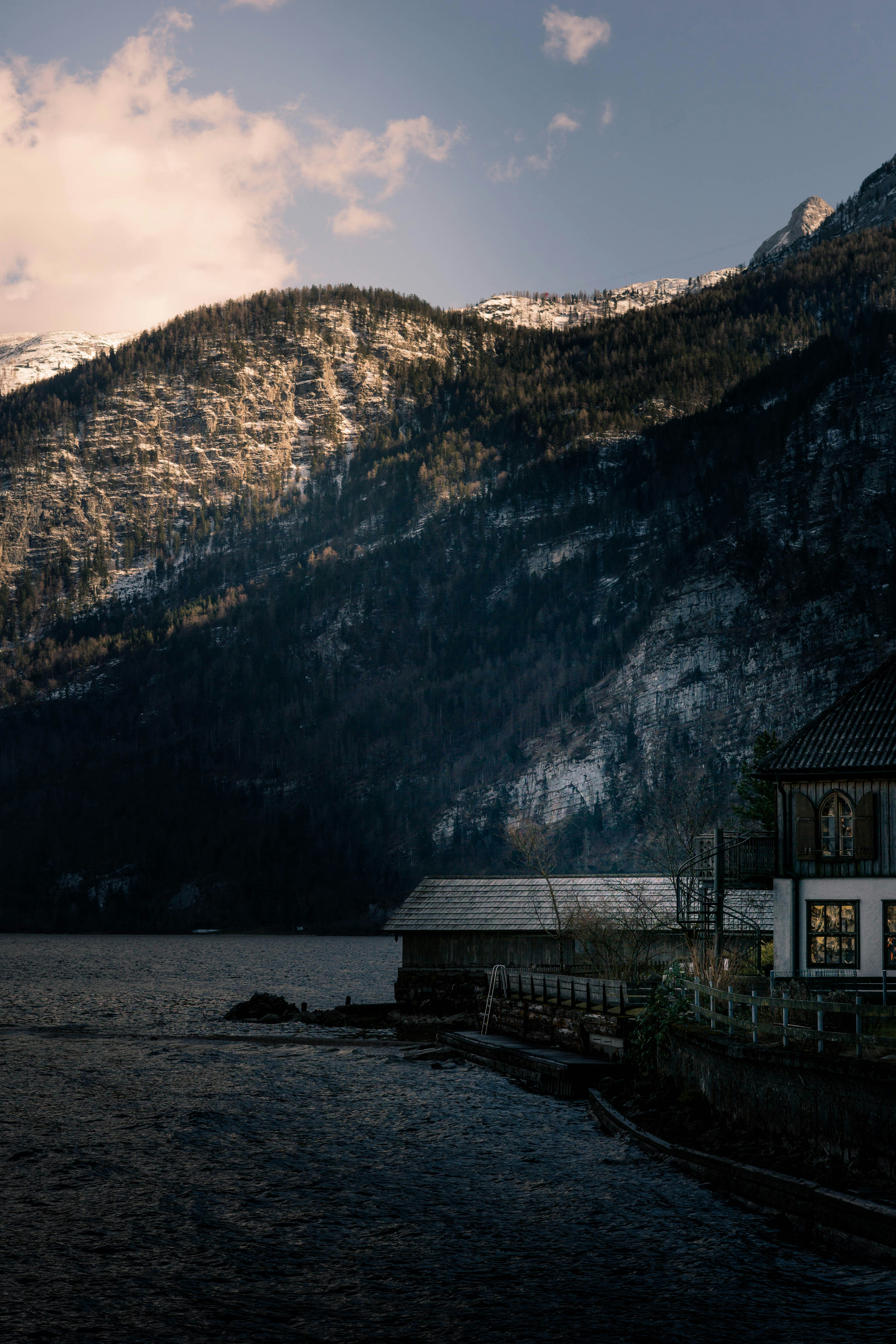 brown wooden house near body of water and mountain