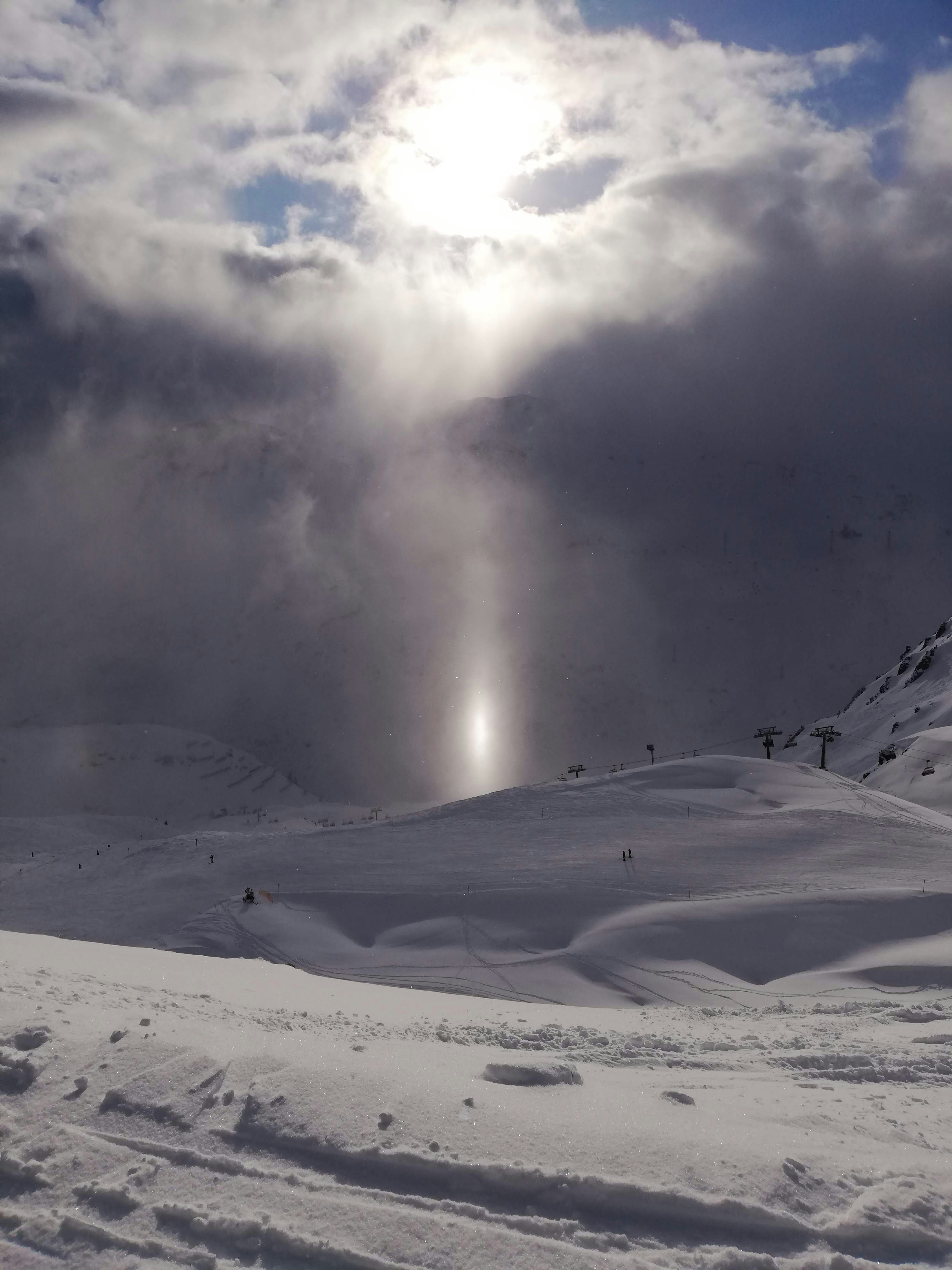 Solar Shaft Over the Snow: A Vertical Beacon in the Clouds