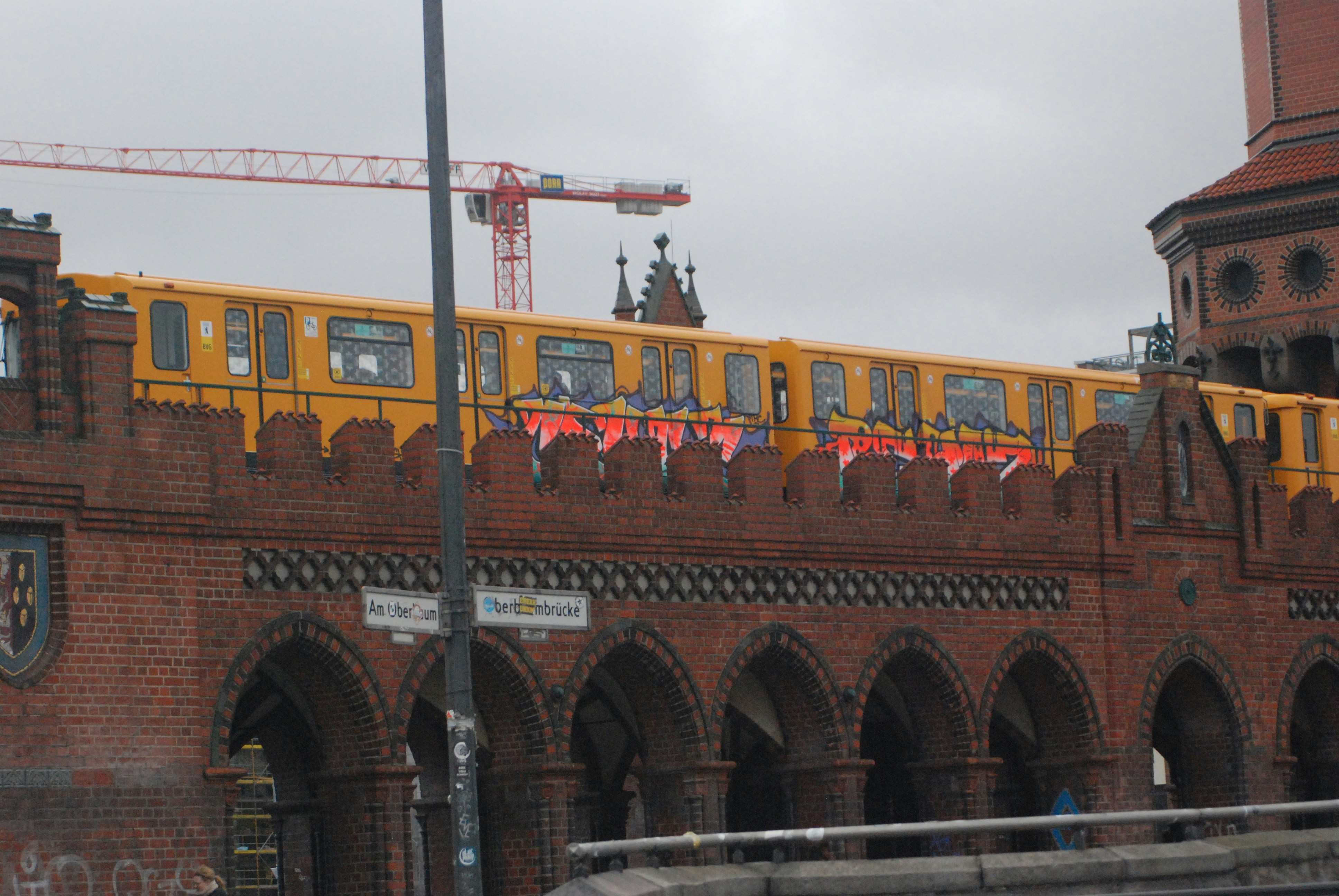 Yellow Railcar Crossing a Wave of Red-Brick Arches Under a Leaden Sky