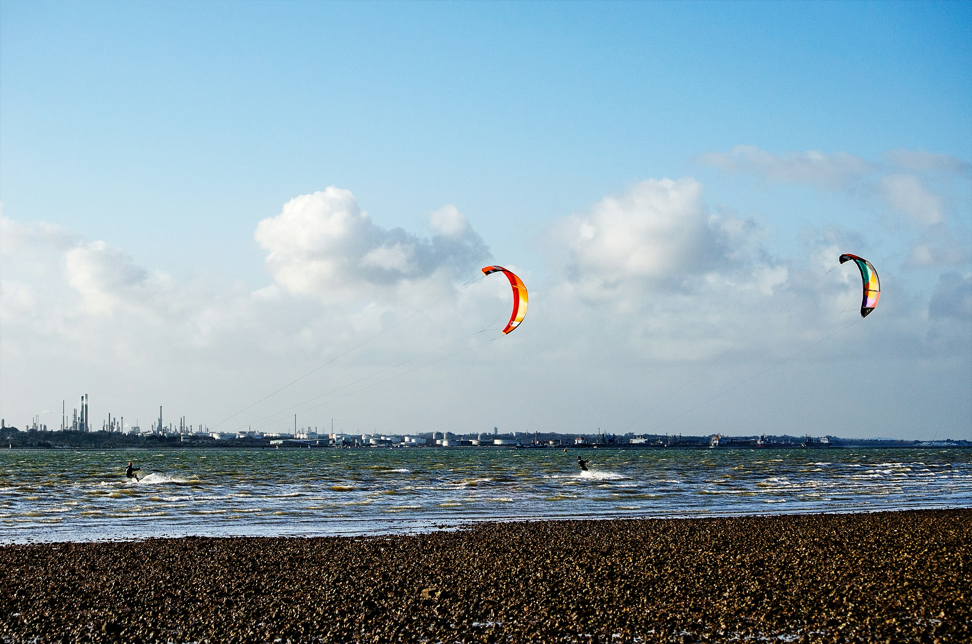 Kites Over Pebbles: Wind-Swept Color over a Quiet Seashore