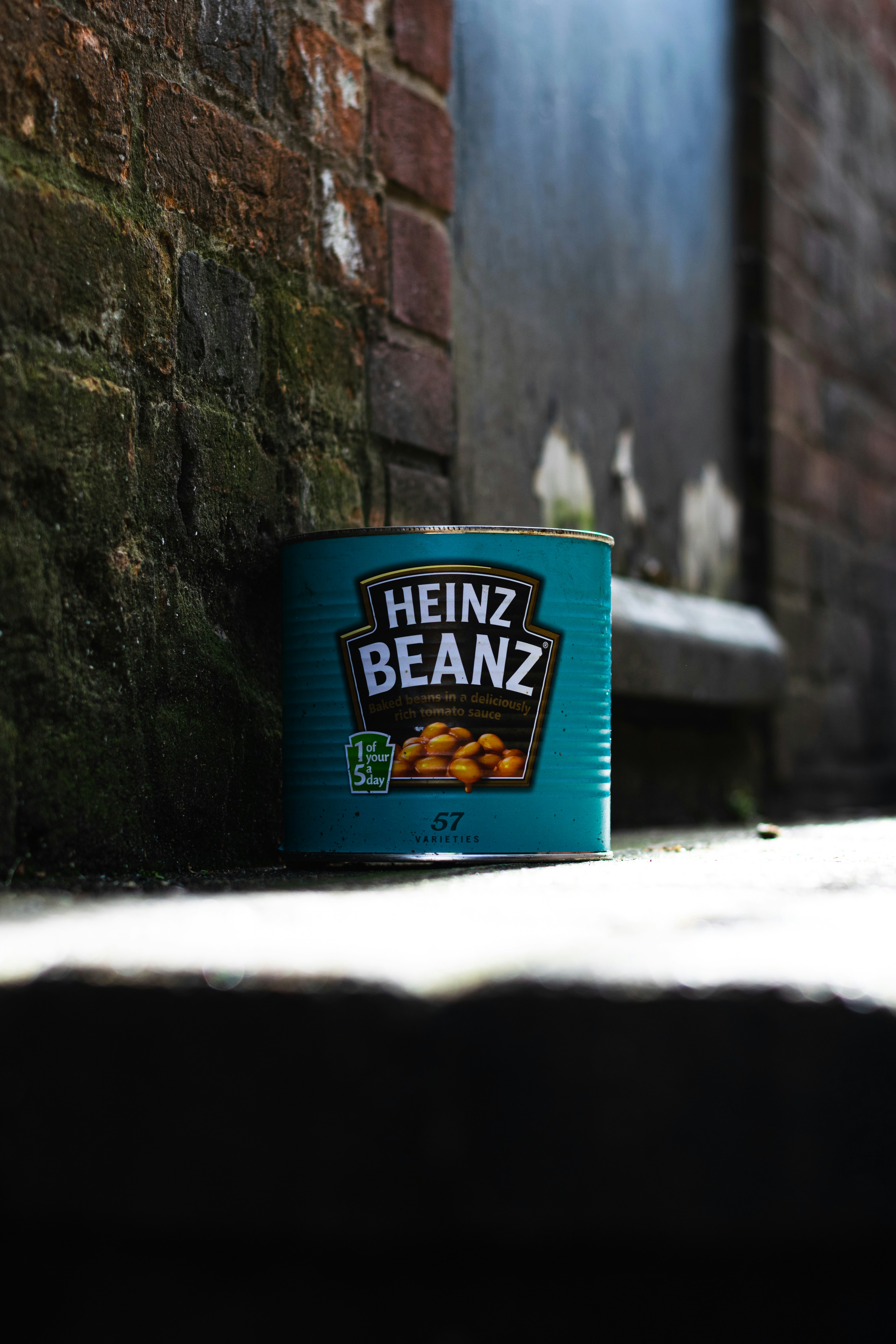 A vintage Heinz Beanz can resting against a textured brick wall, evoking a sense of urban decay and nostalgia.