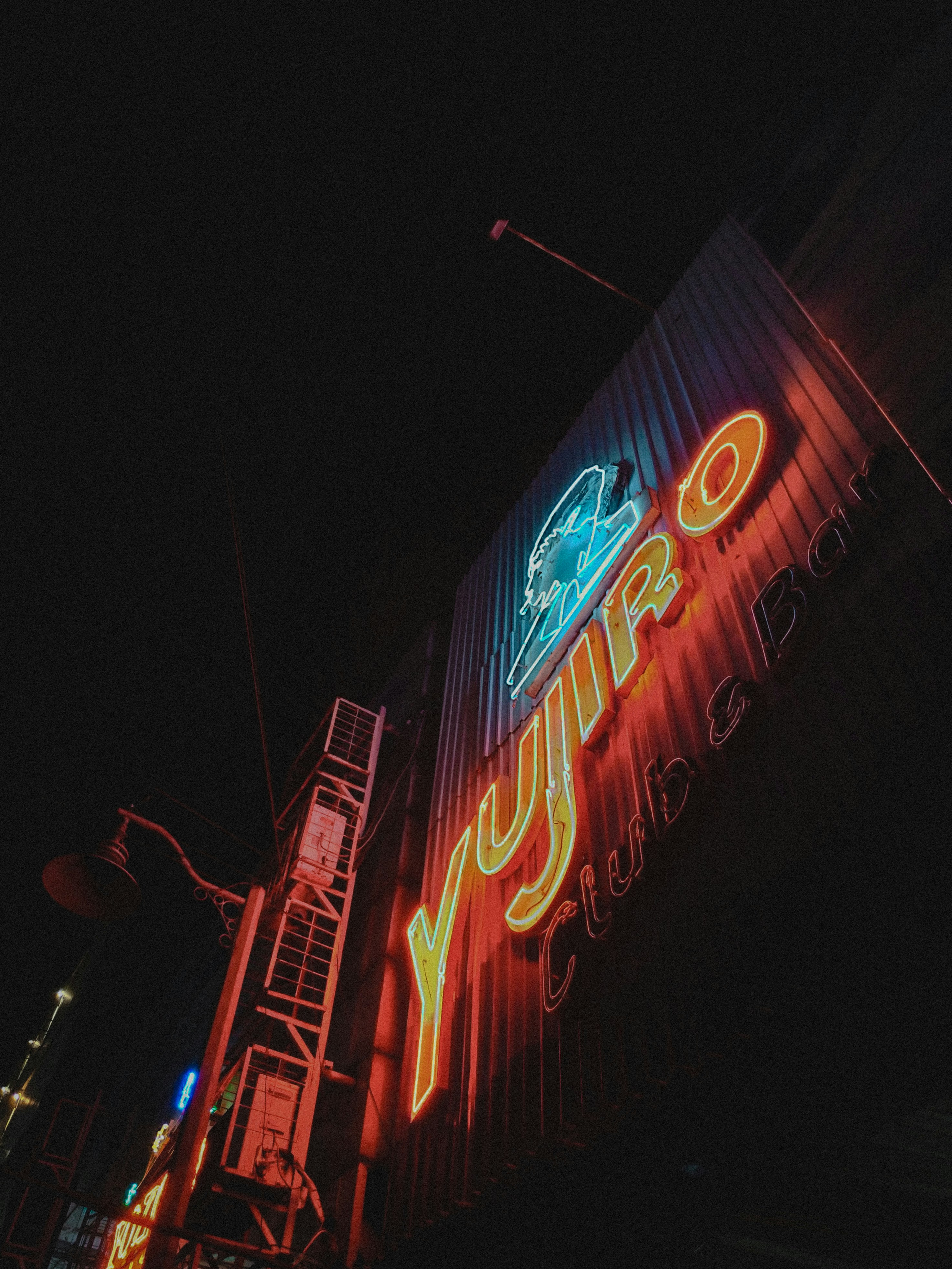 Illuminated neon sign of 'Yujiro Club & Bar' against a dark backdrop, showcasing nightlife allure.