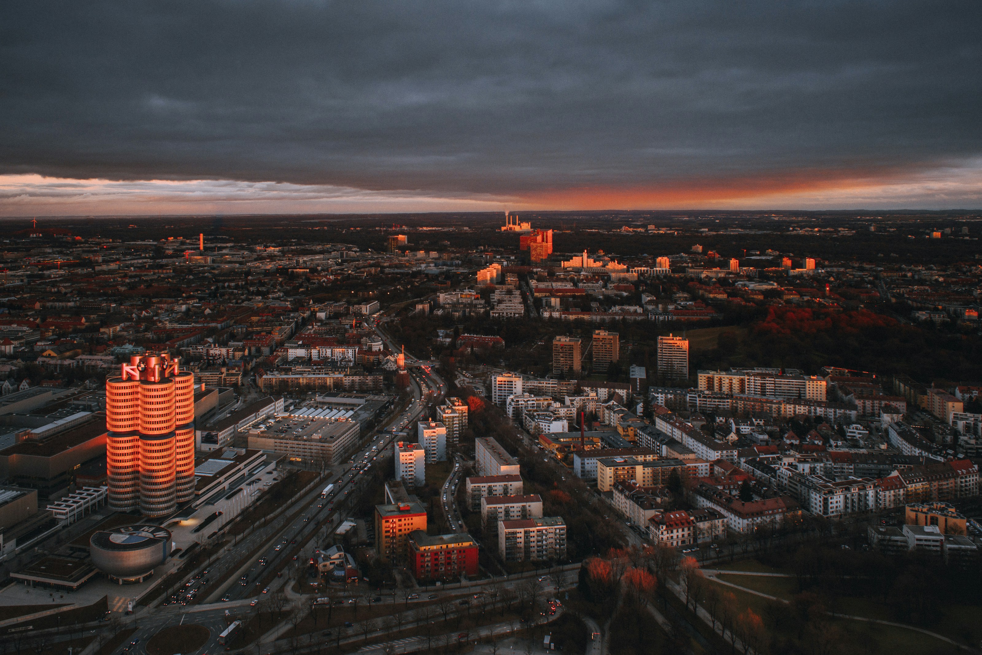 City skyline at dusk with dramatic clouds and warm light reflecting on buildings.