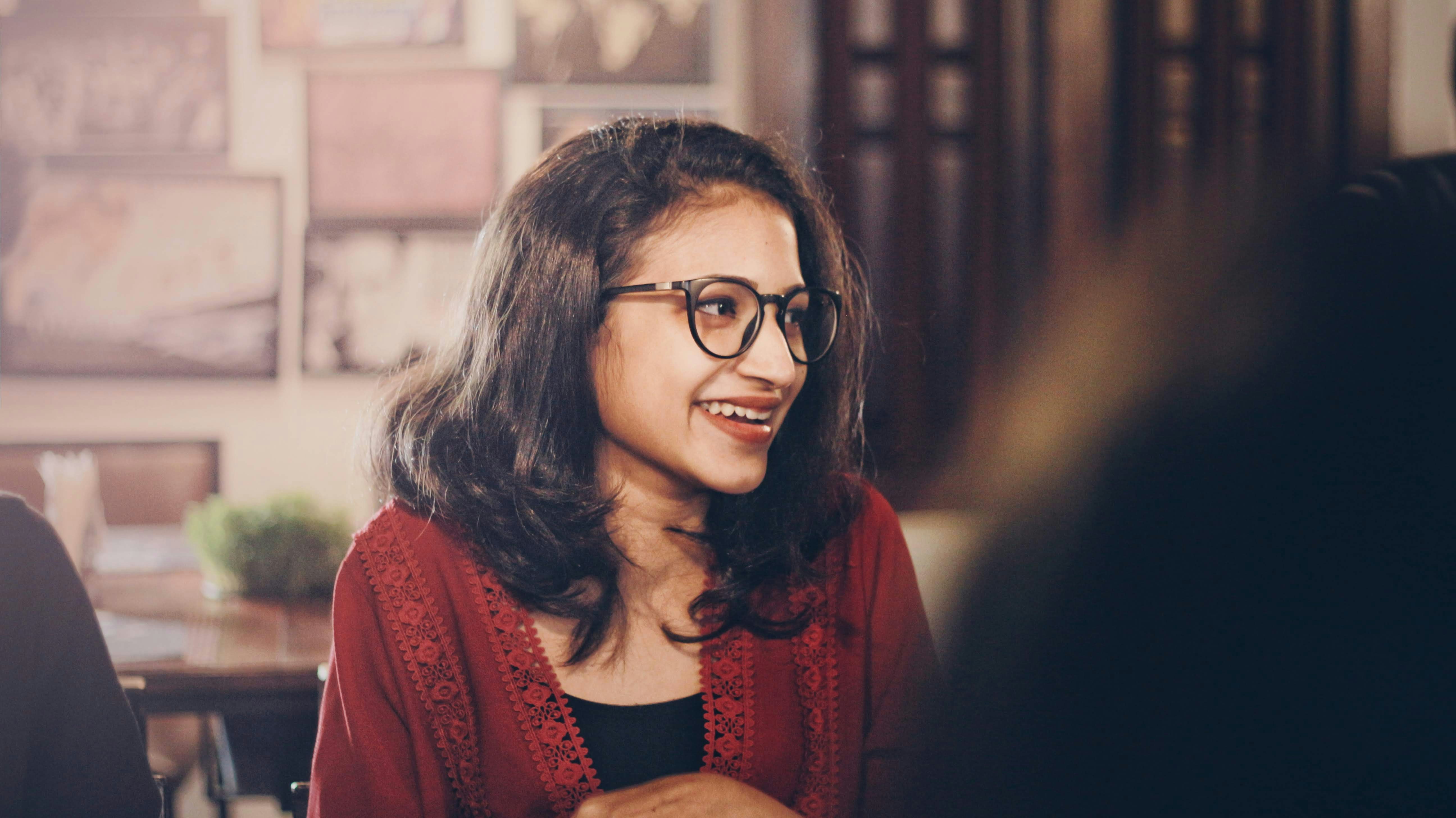 Girl smiling | woman in red cardigan wearing black framed eyeglasses