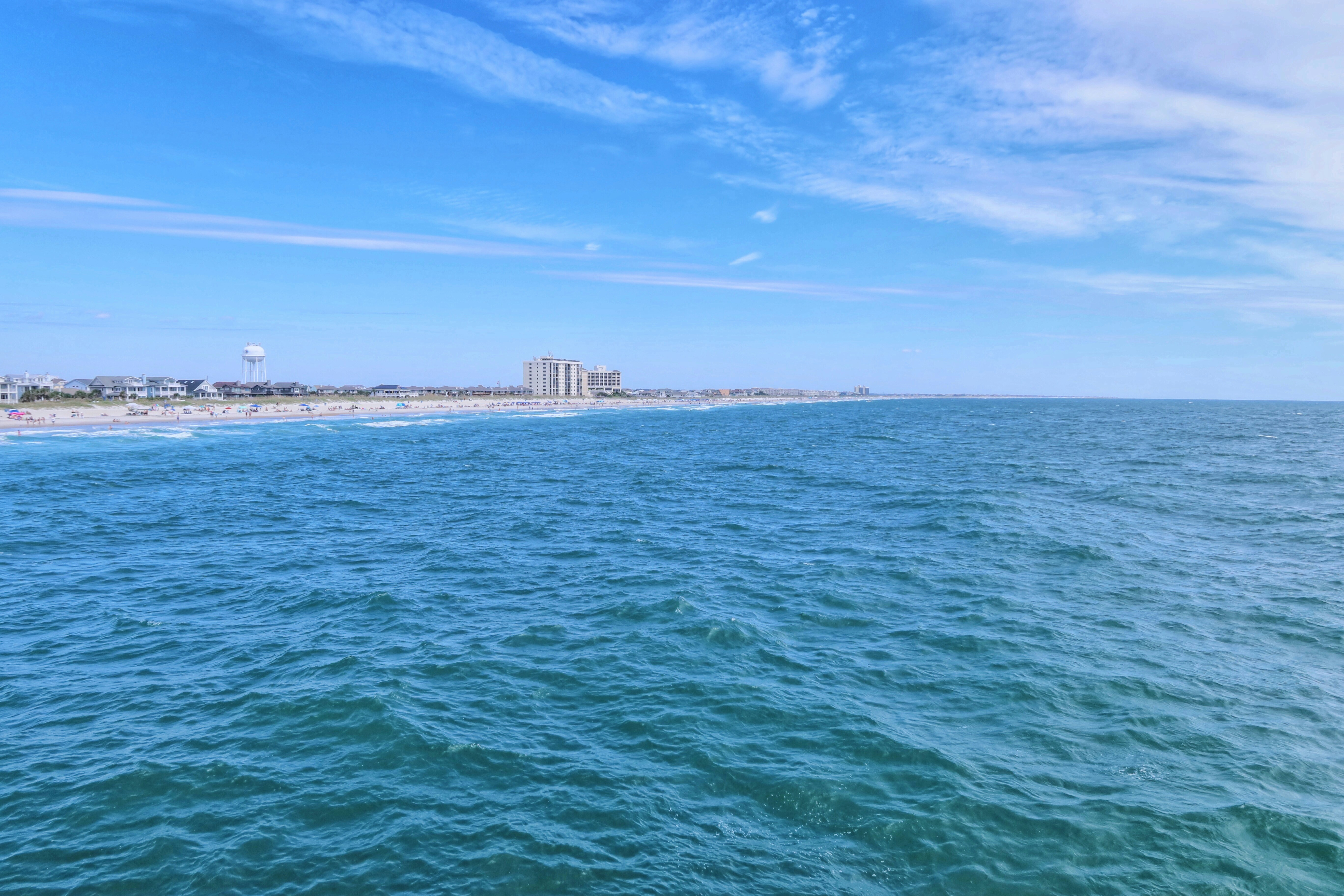 Expansive view of the ocean with a distant shoreline under a partly cloudy sky.