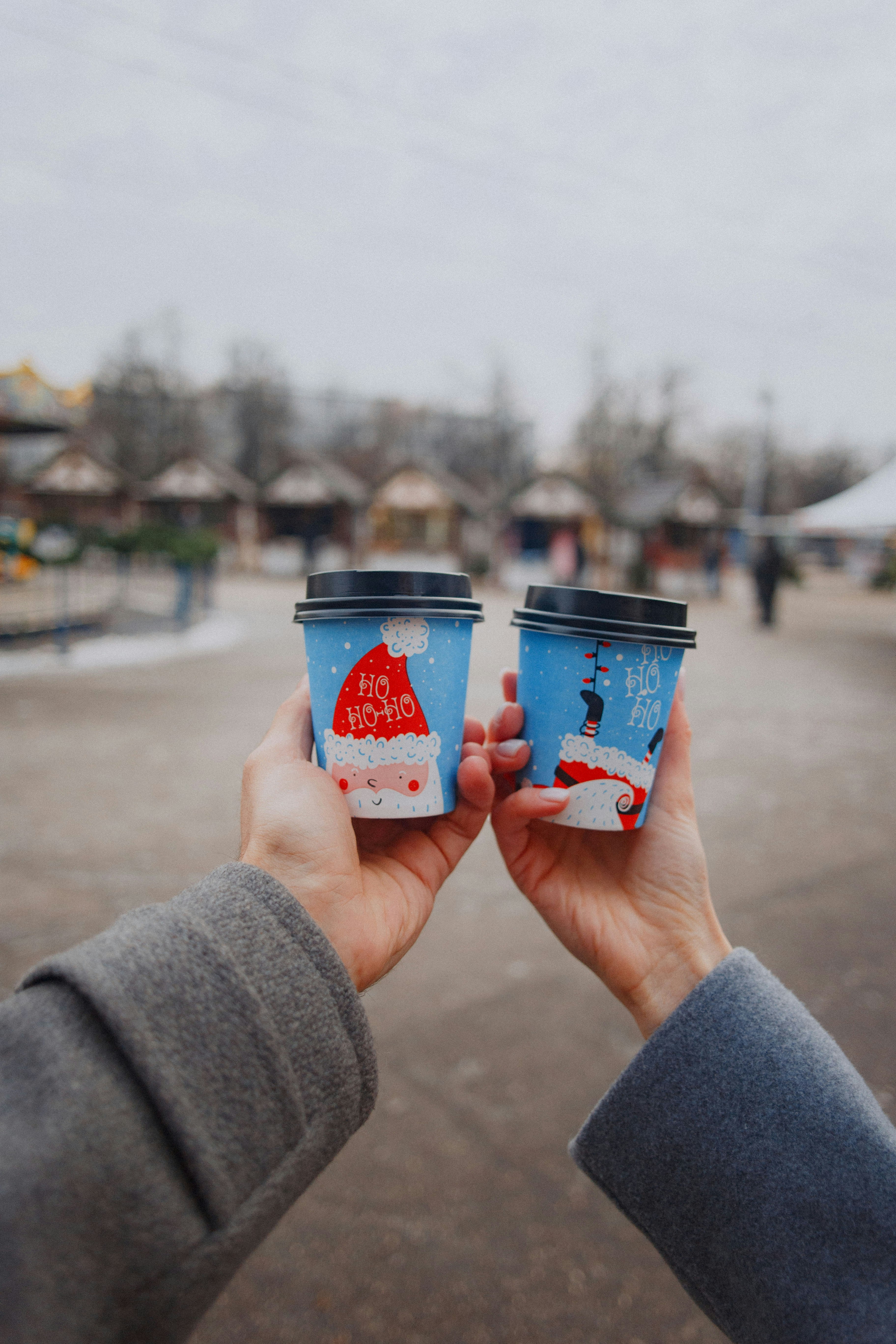 Two Festive Coffee Cups Framed by a Snowy Winter Market