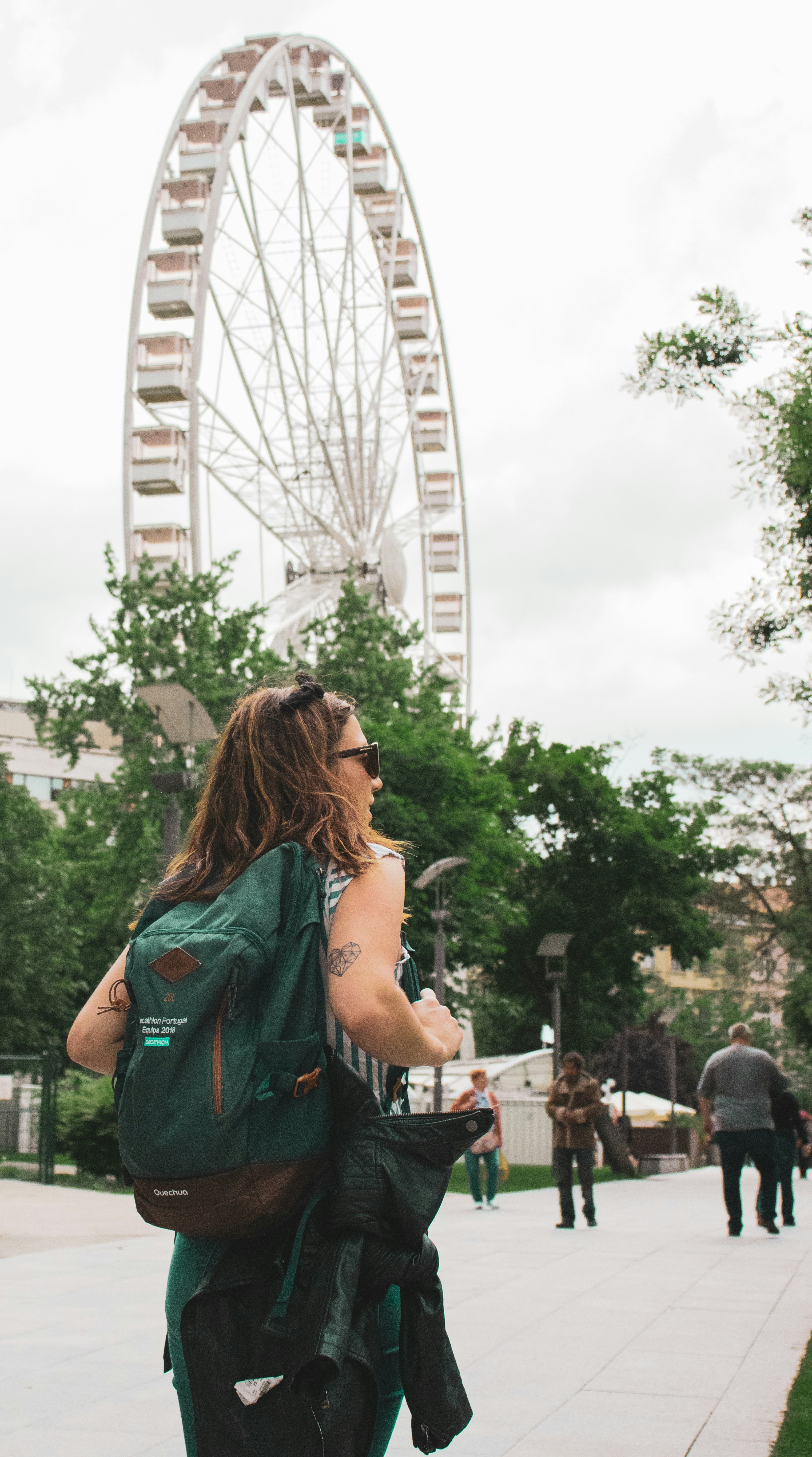 Backpacker in a city park, framed by a towering Ferris wheel