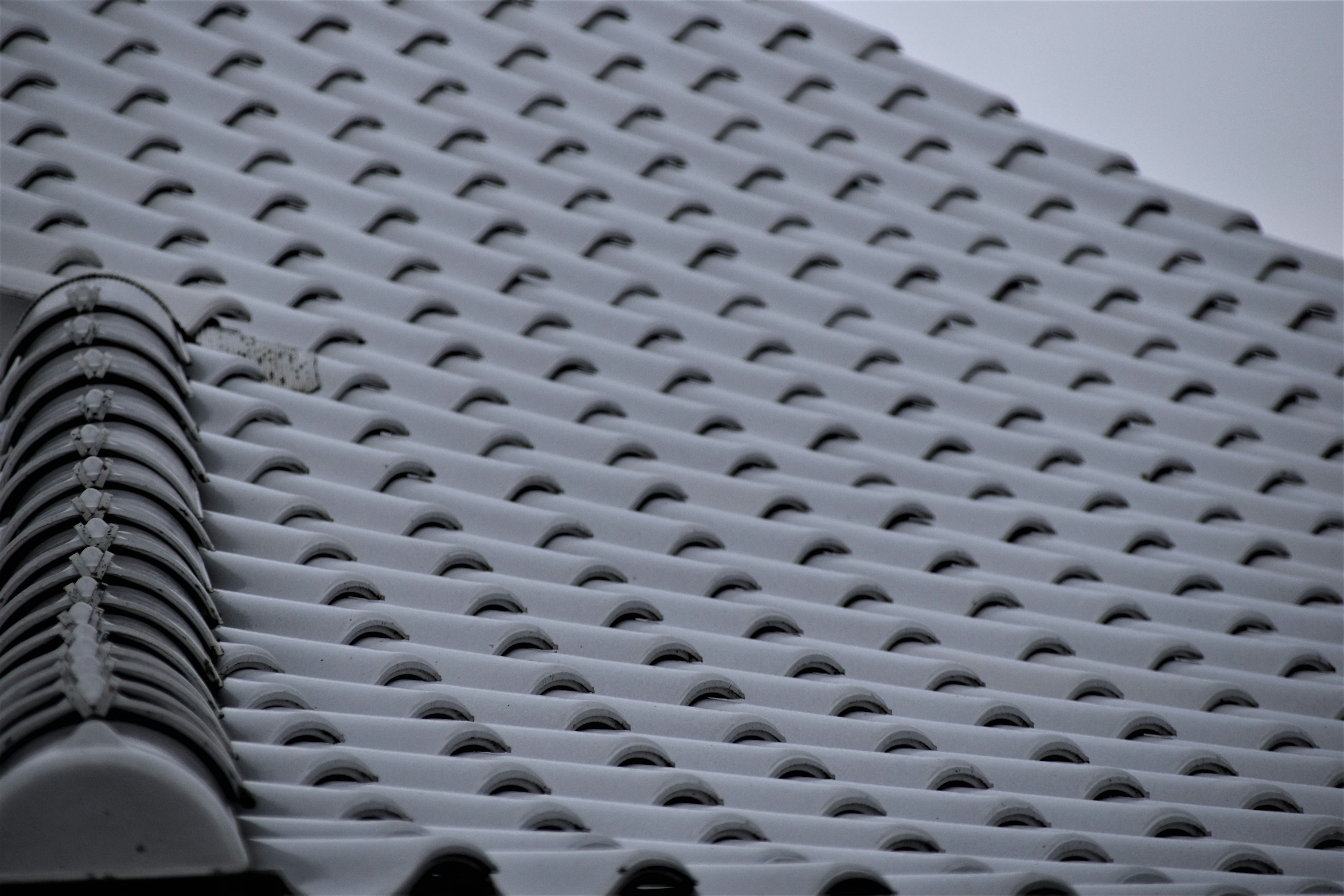 Close-up of a ceramic tile roof showcasing its wavy texture and uniform pattern. The image emphasizes the craftsmanship and design of traditional roofing.