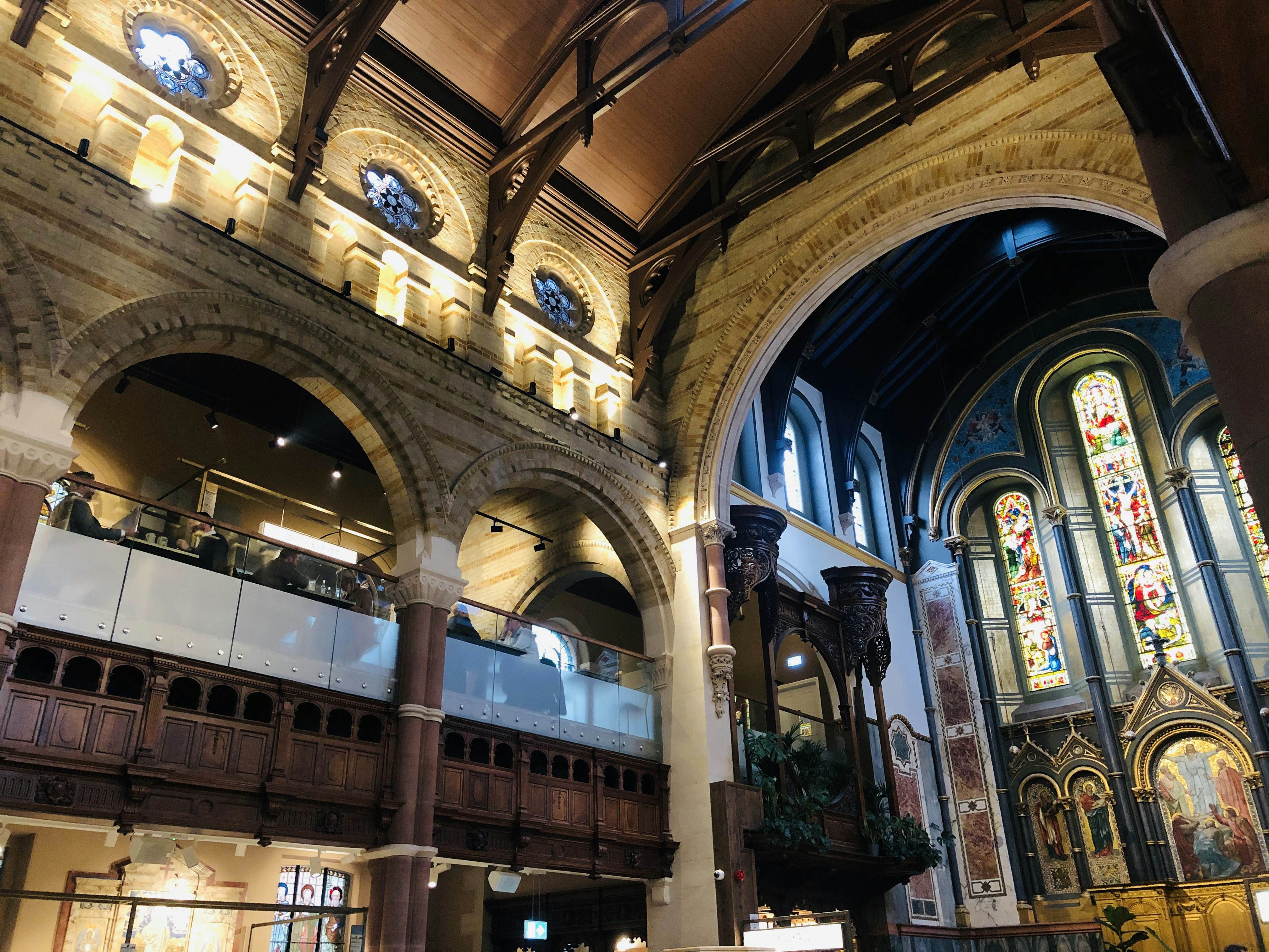 Interior of a historic building featuring grand arches, stained glass windows, and a blend of contemporary design elements.