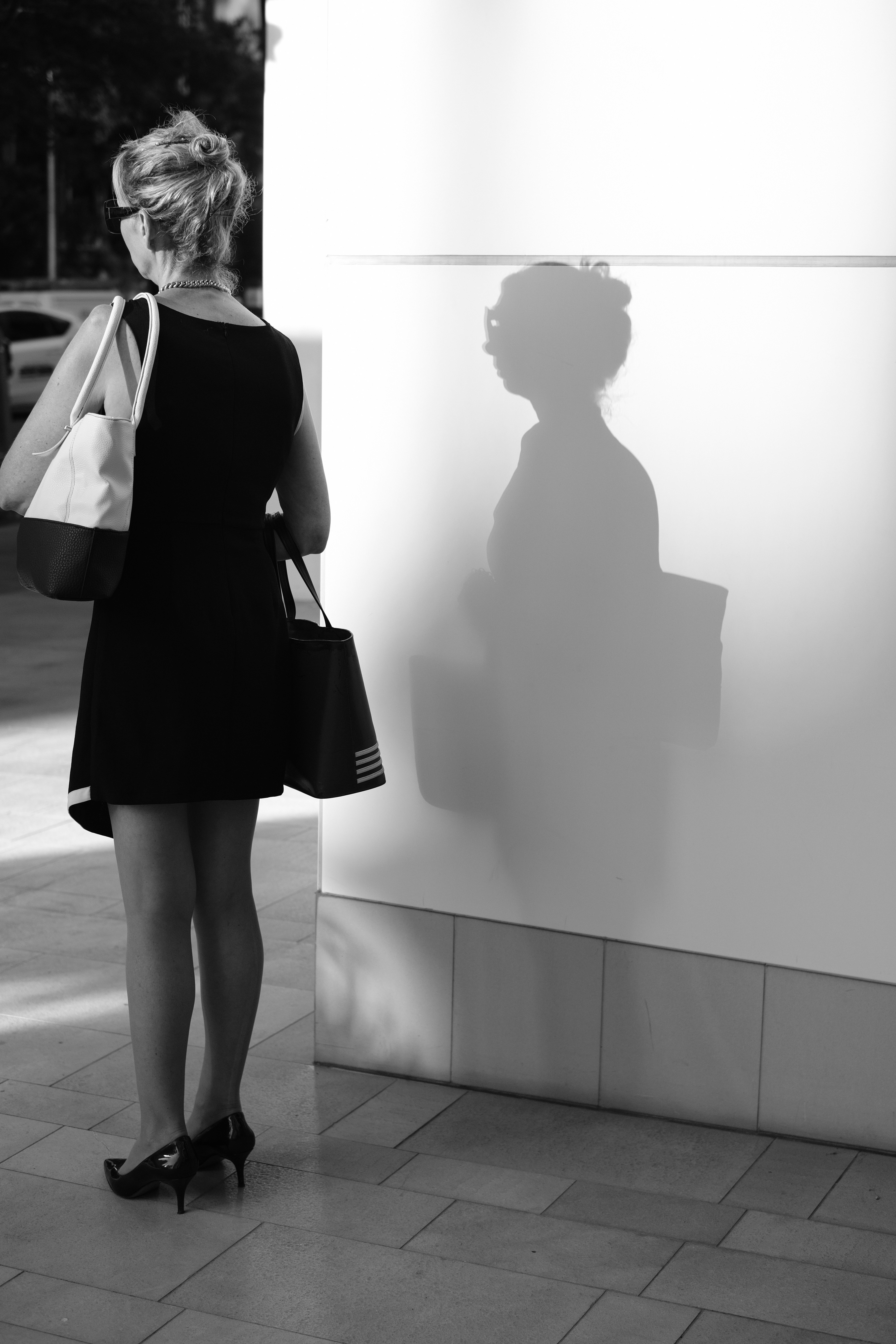 Parallel Echoes: A Woman in Black and Her Shadow on a White Wall