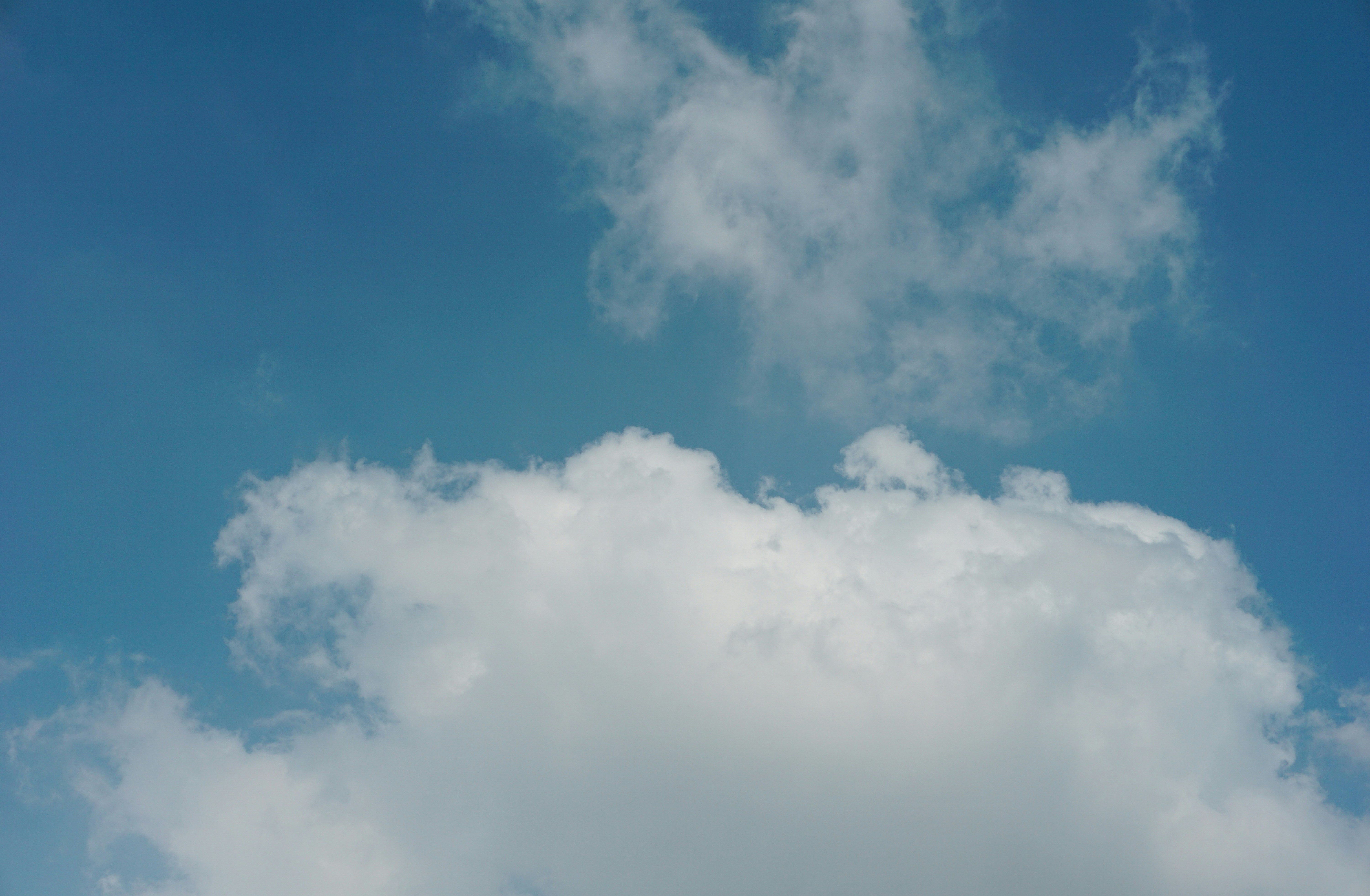 Fluffy white clouds drifting across a bright blue sky, creating a serene atmosphere.