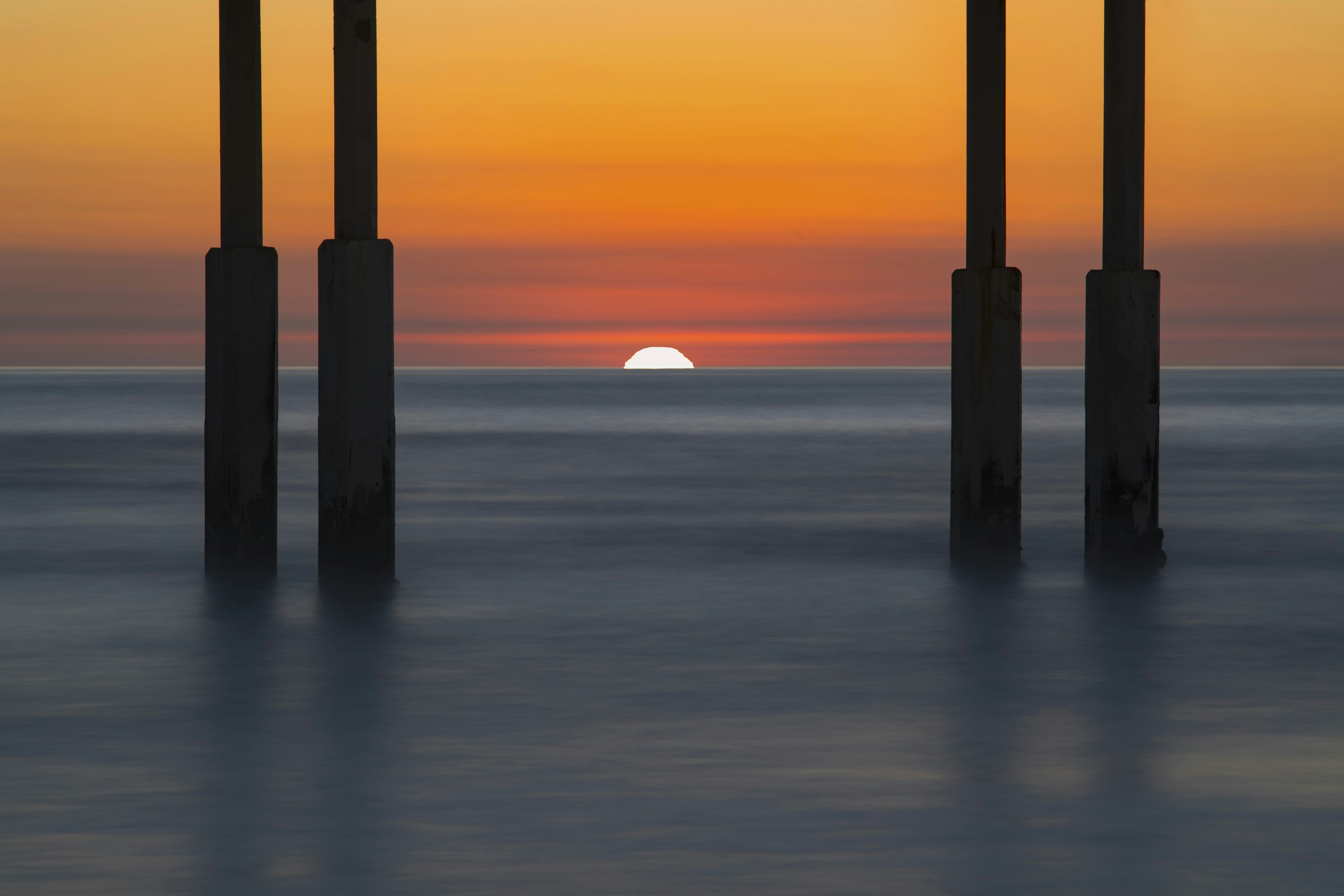 Crimson Horizon Between Silent Pier Pillars