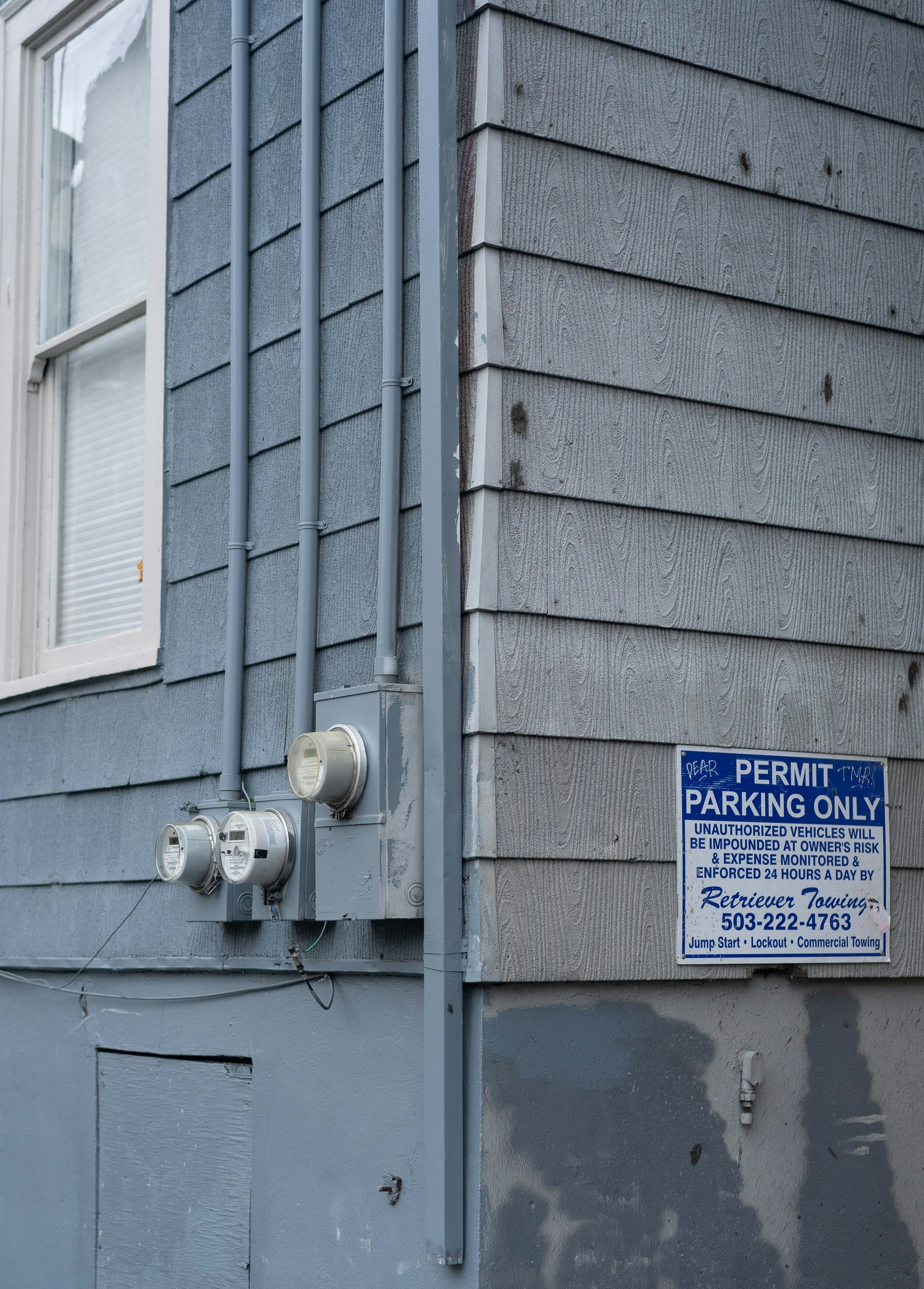 Corner Confluence: A Weathered Blue Facade with Meters and a Parking Sign