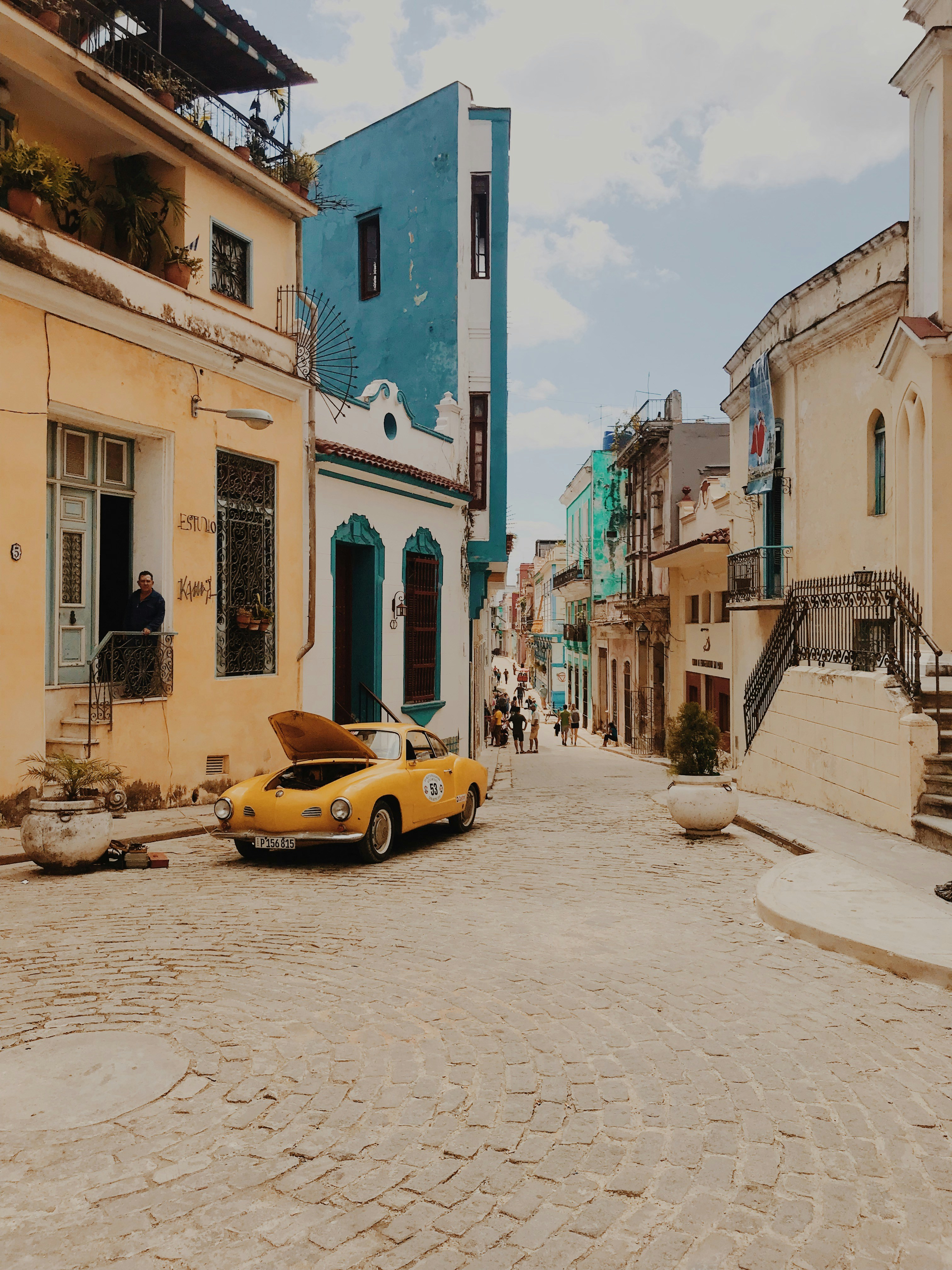 Sunlit Cobblestones and a Yellow Cabriolet in a Colorful Coastal Street