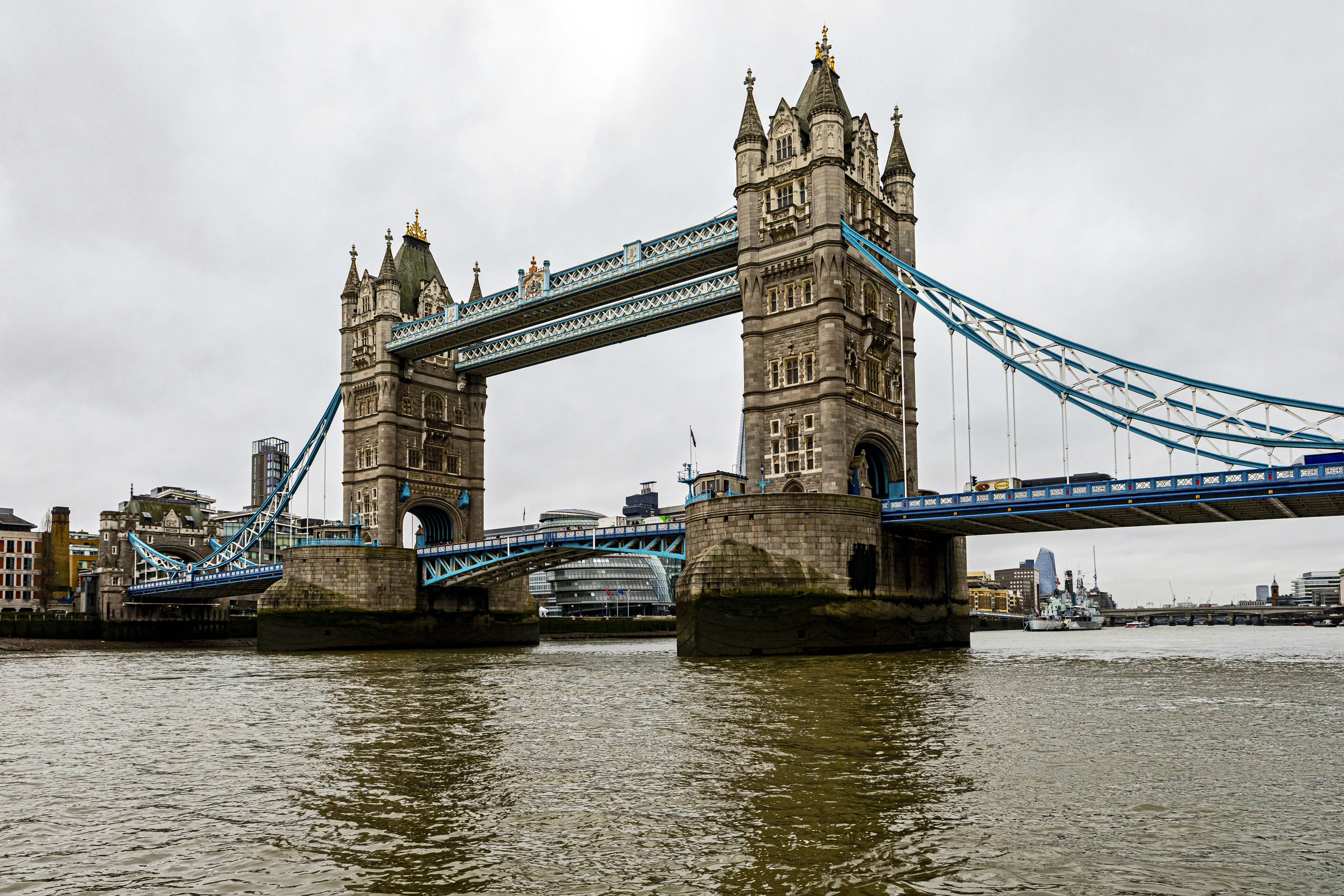 Tower Bridge stands majestically over the Thames River, showcasing its distinct Gothic architecture and vibrant blue accents.