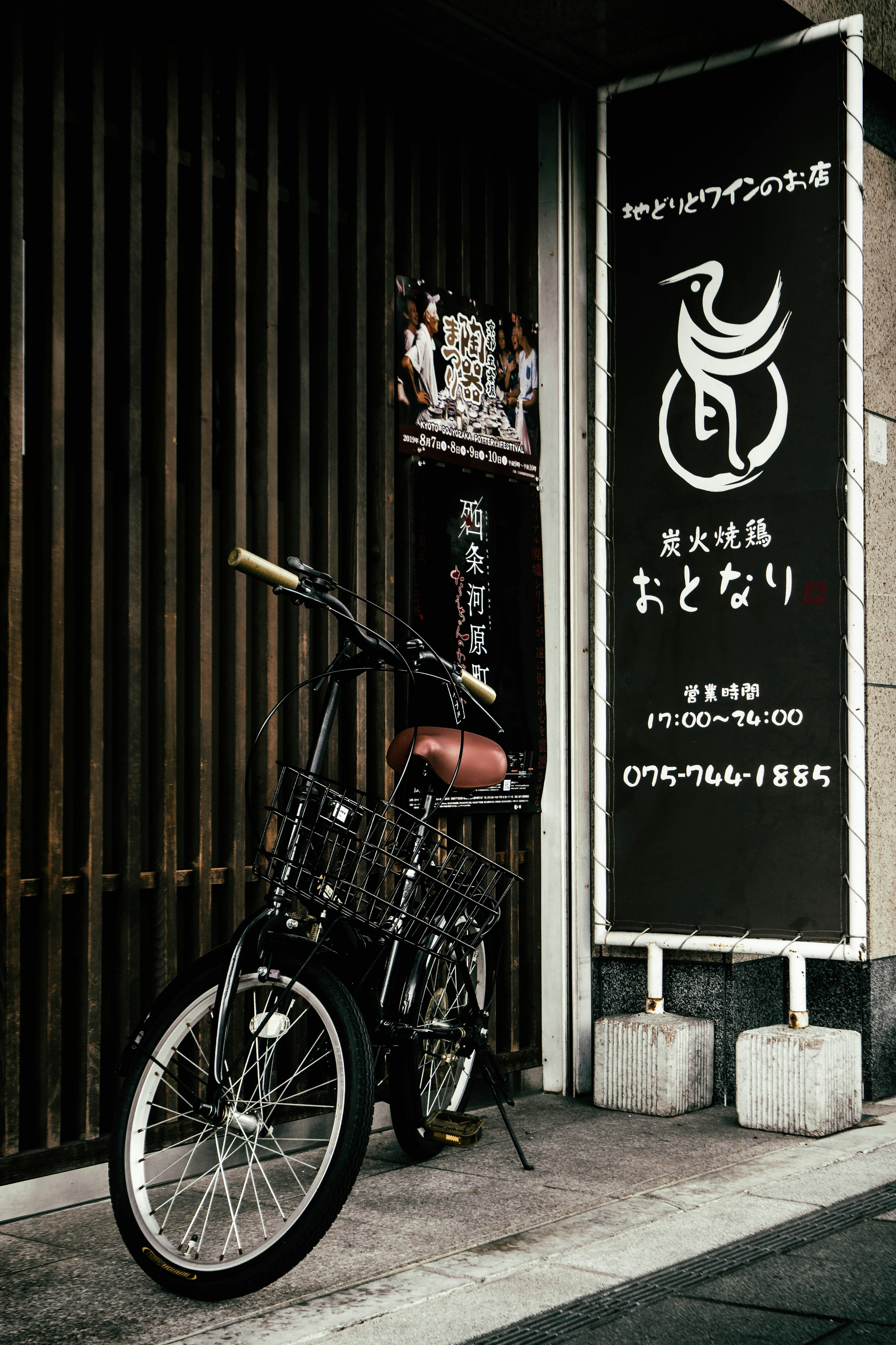 A vintage bicycle rests against a wall adorned with a restaurant sign, showcasing a blend of urban life and artistic signage.