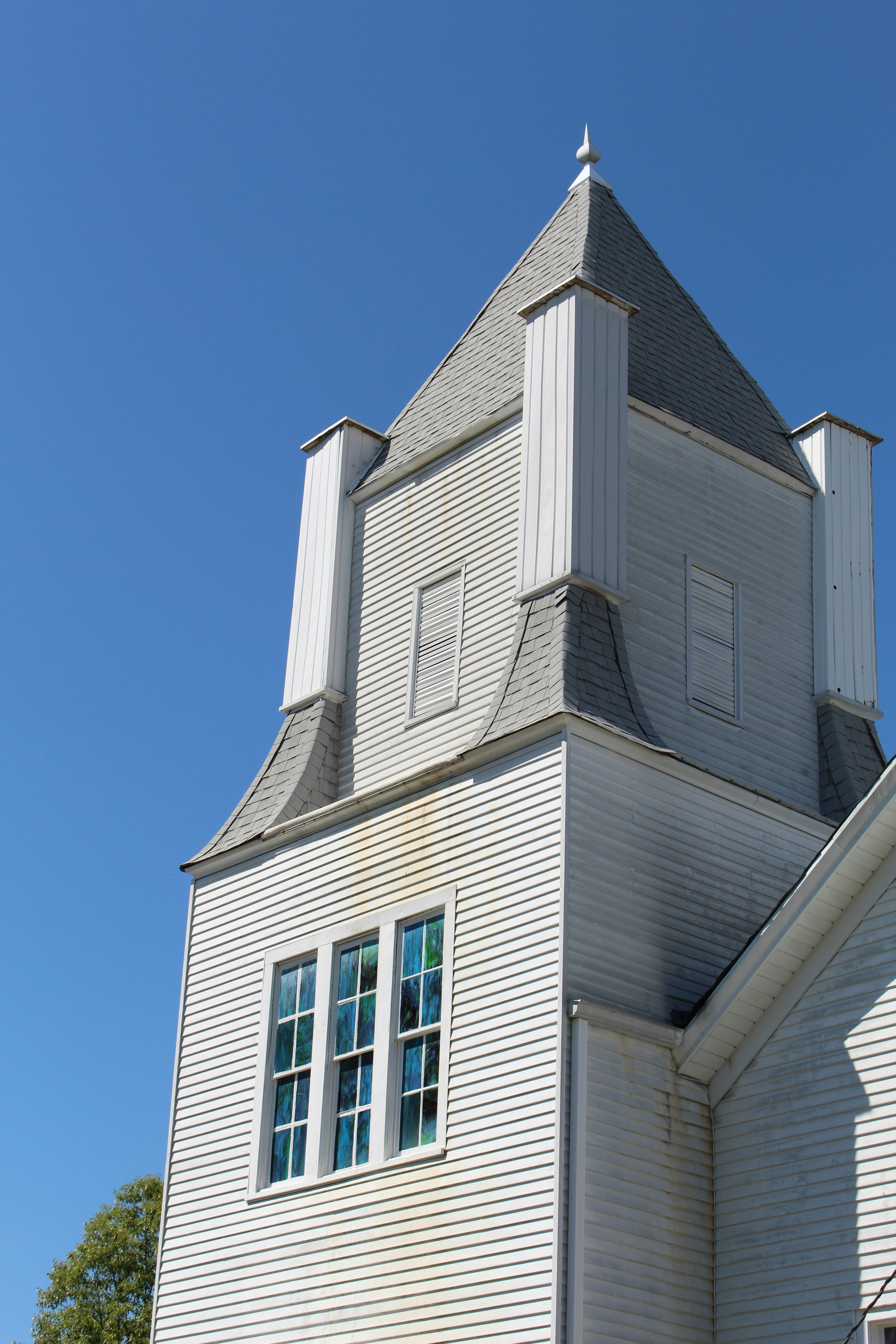 A vintage church with a unique tower design, showcasing intricate architectural details against a clear blue sky.