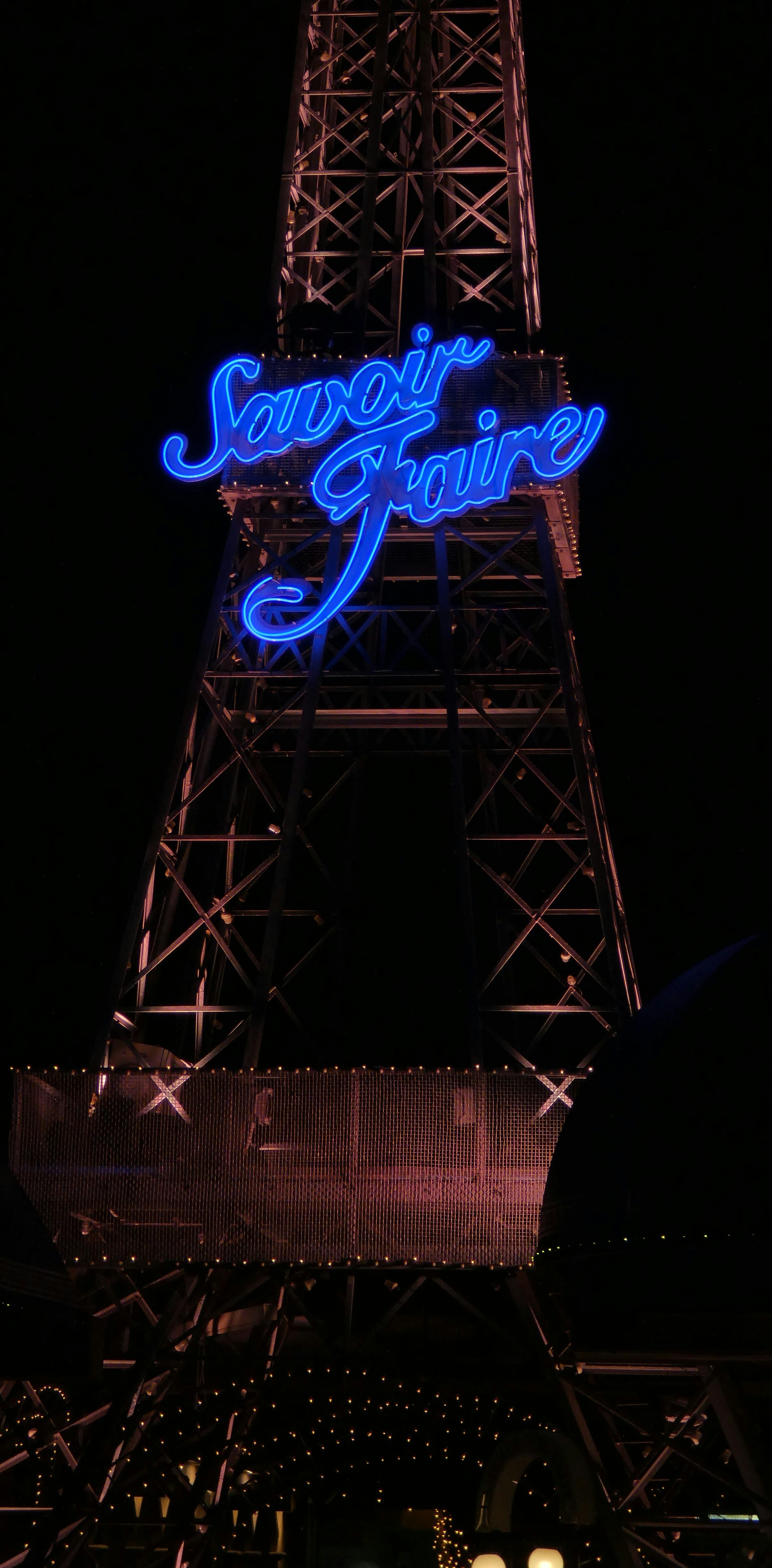 Neon Skyline: Swaying Sapphire Sign on a Nighttime Tower