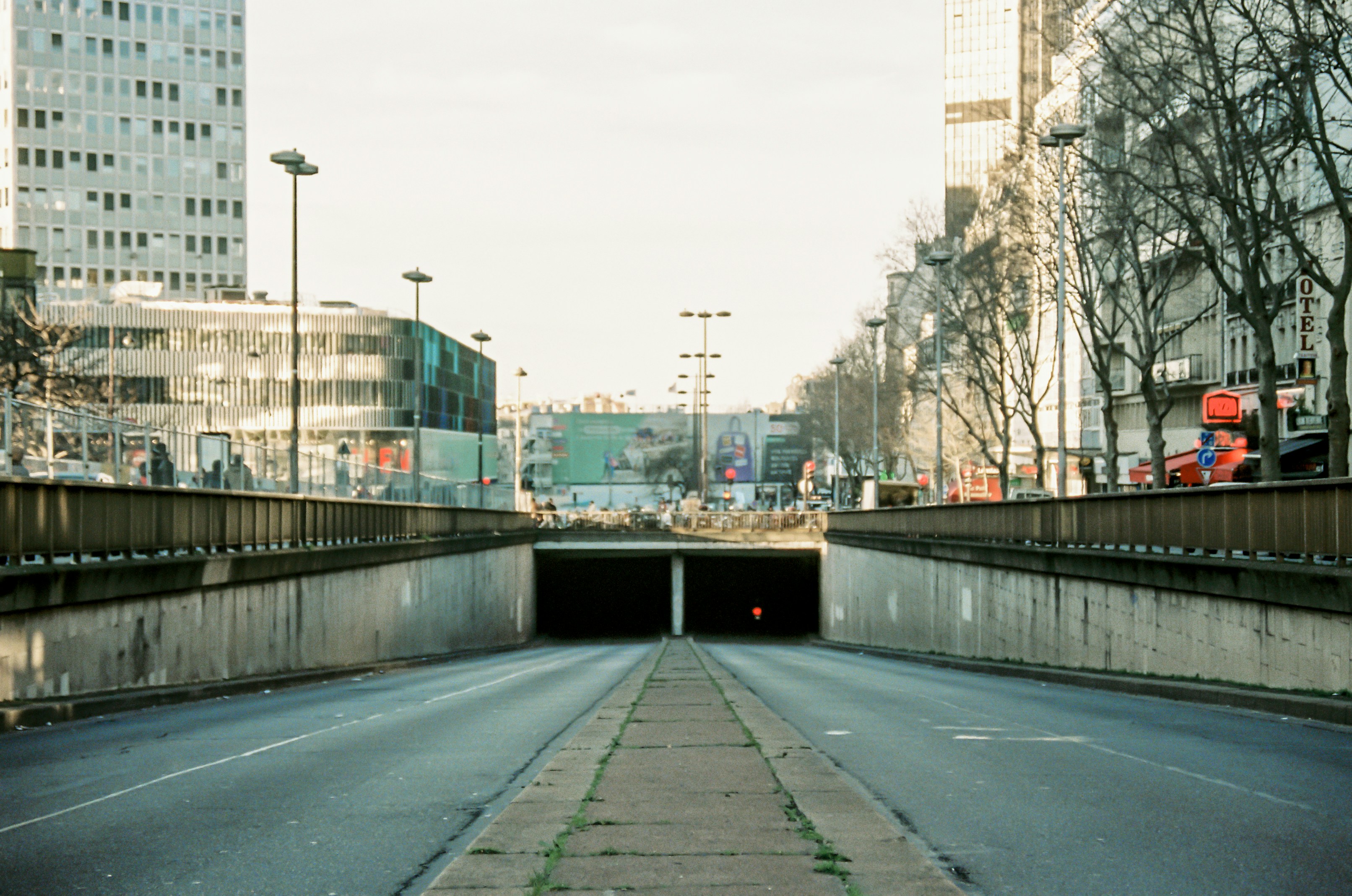 A wide view of an urban tunnel entrance flanked by modern buildings, showcasing the contrast between underground routes and city life above. The scene captures the essence of urban exploration.