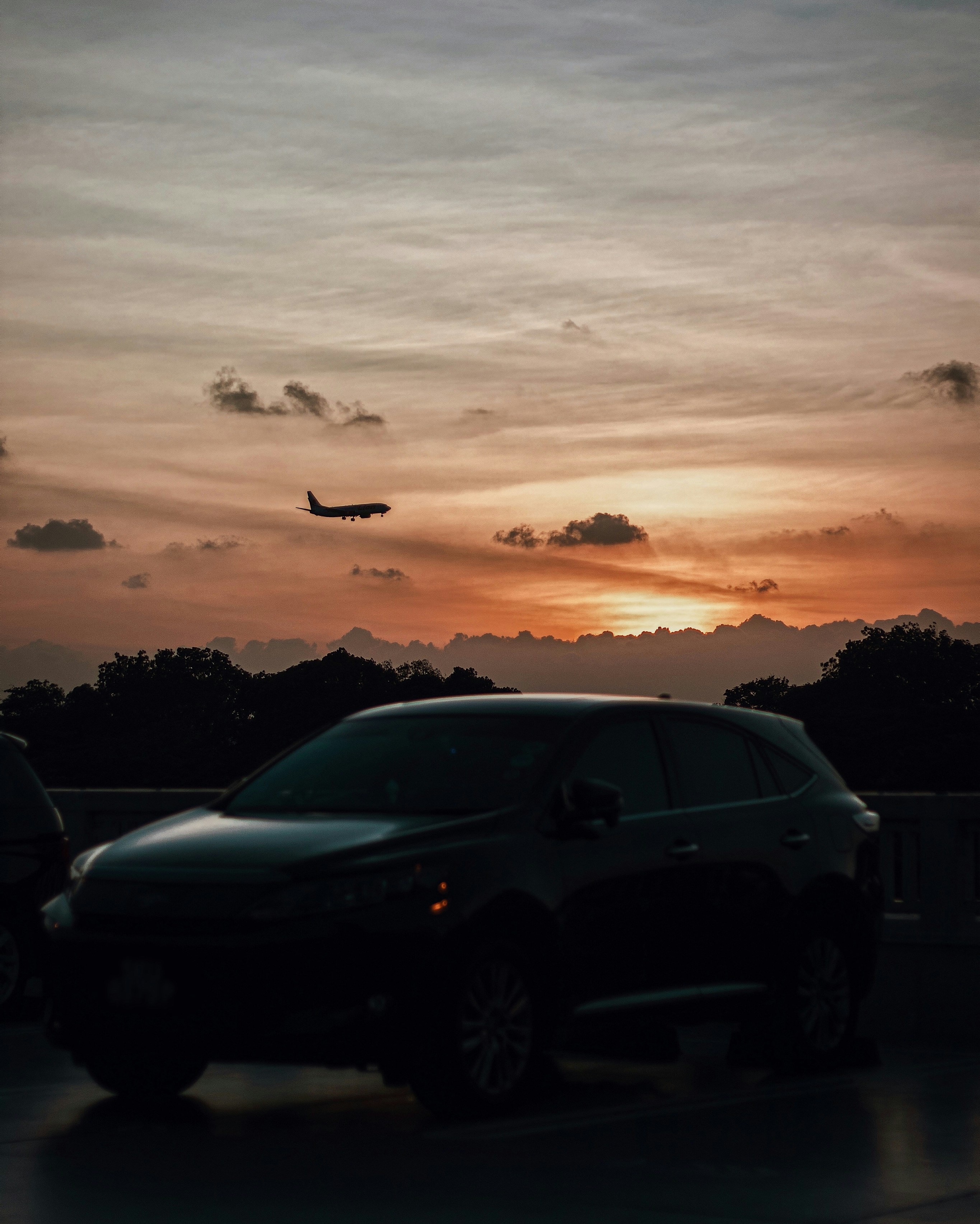 Ember Skyway: An Airplane Traces the Sunset Above a Quiet Highway