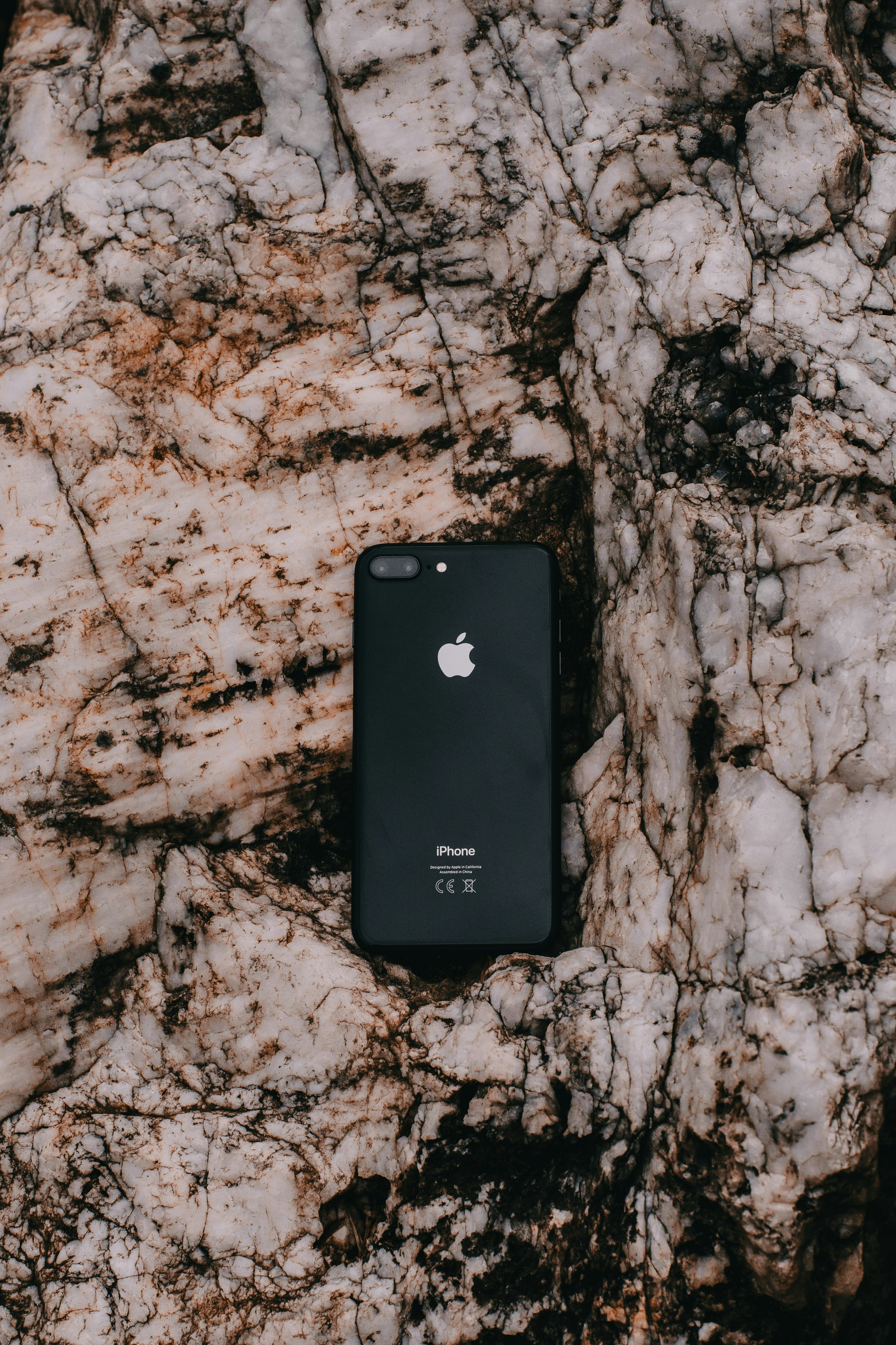 Jet-Black iPhone Resting on a Rugged Rock Canvas