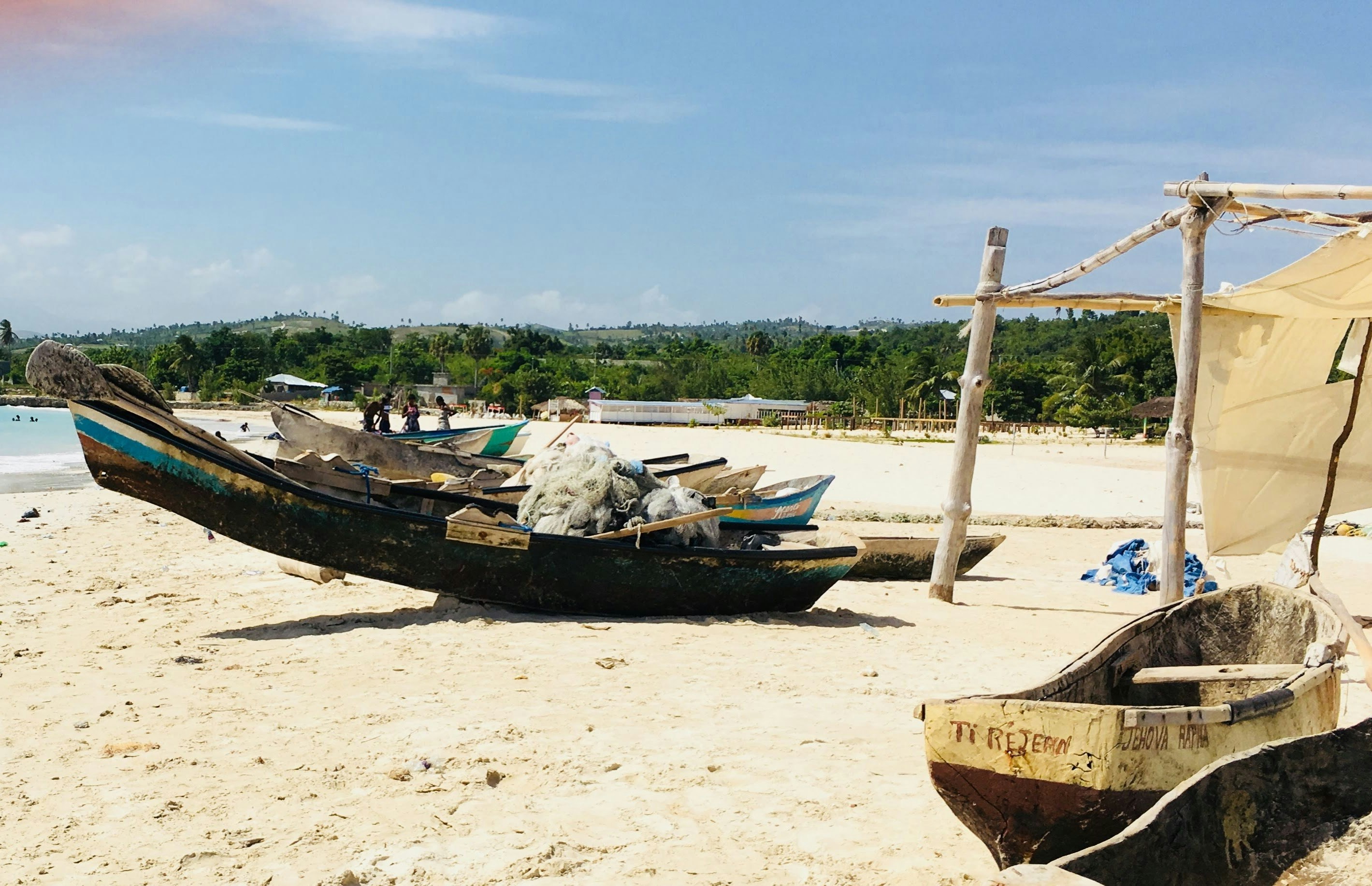 Traditional fishing boats resting on a sandy beach, surrounded by lush greenery and a tranquil sea. The scene captures the essence of coastal life.