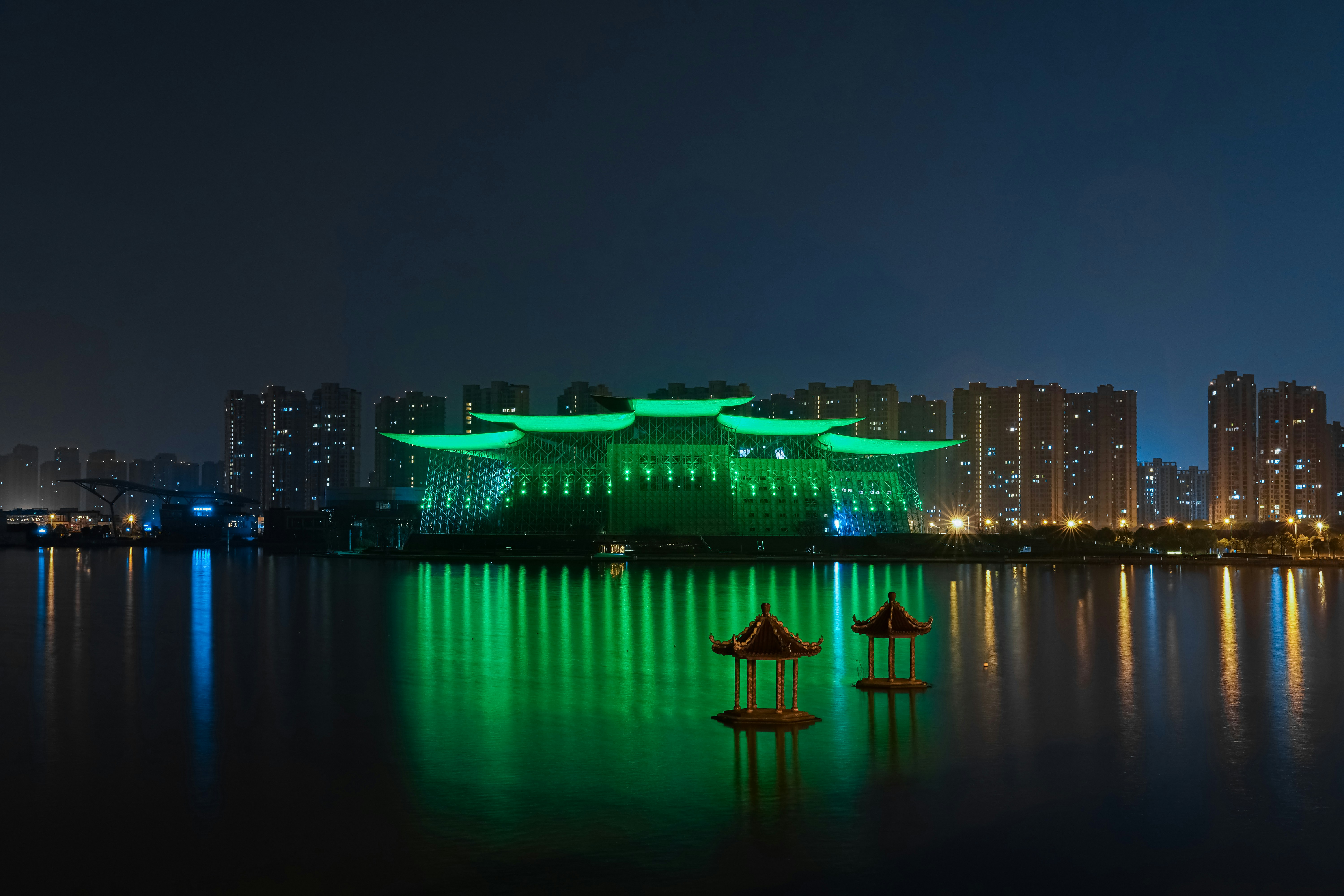 Lighted city buildings near body of water during night time photo ...