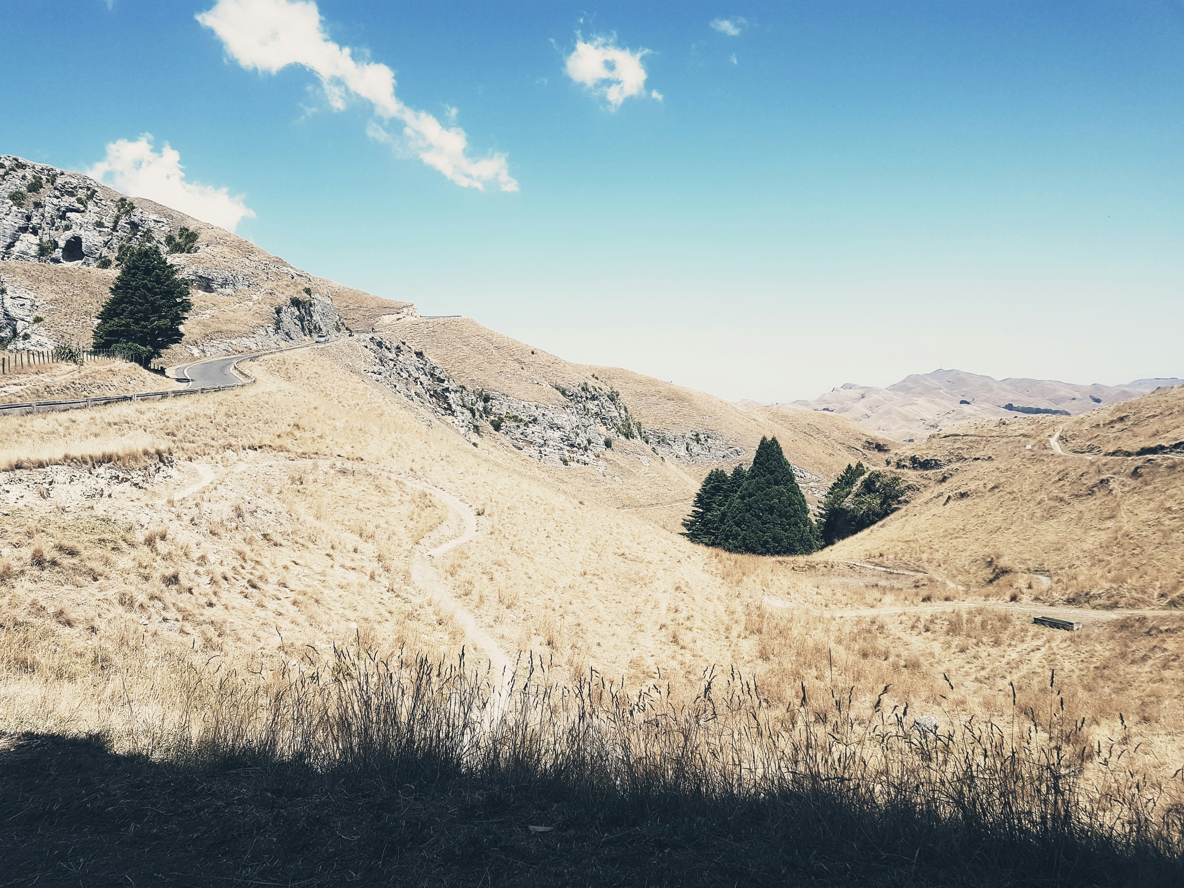 brown grass field near brown mountain under blue sky during daytime