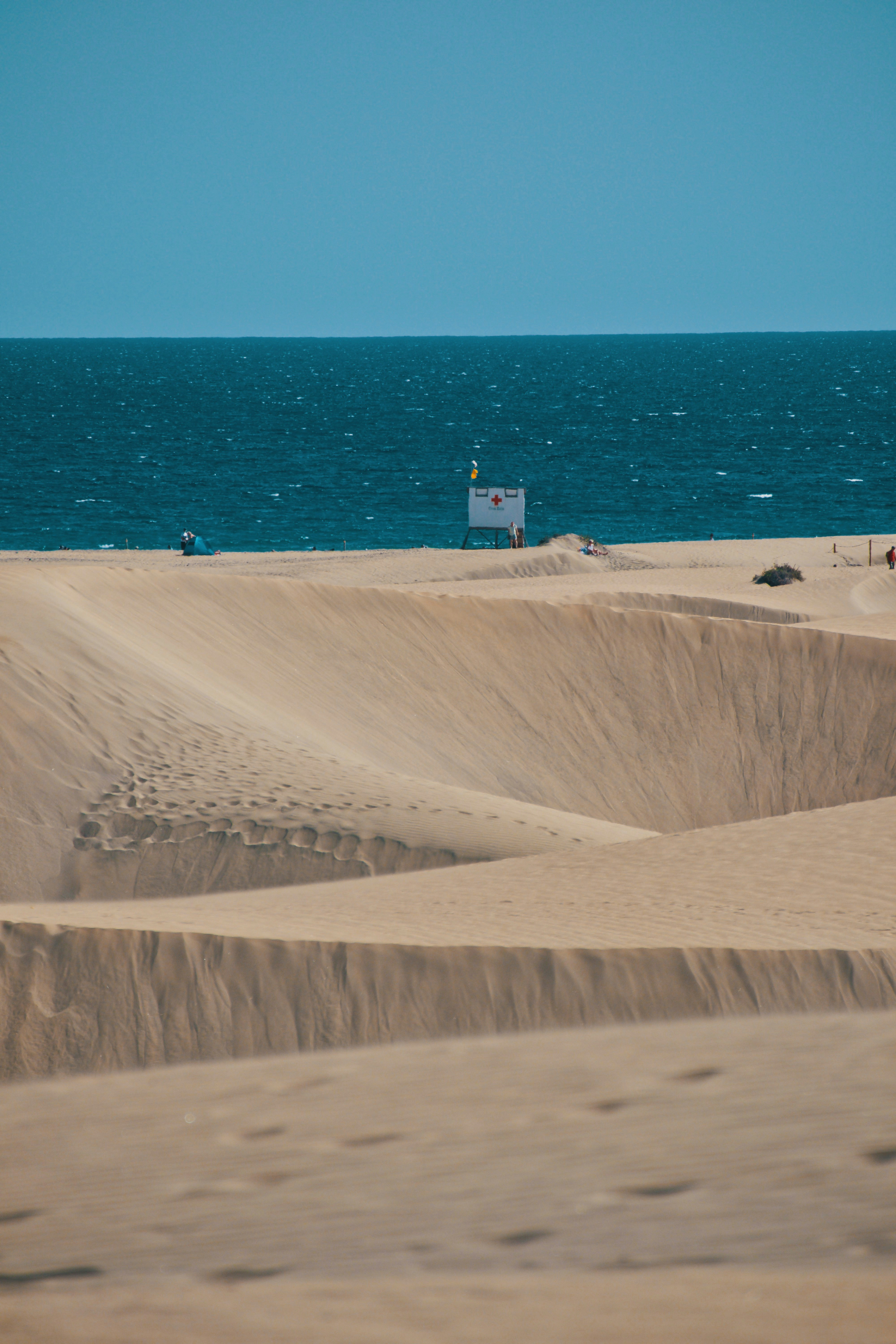 Lifeguard Stand on Wind-Sculpted Dunes Beneath a Calm Blue Horizon
