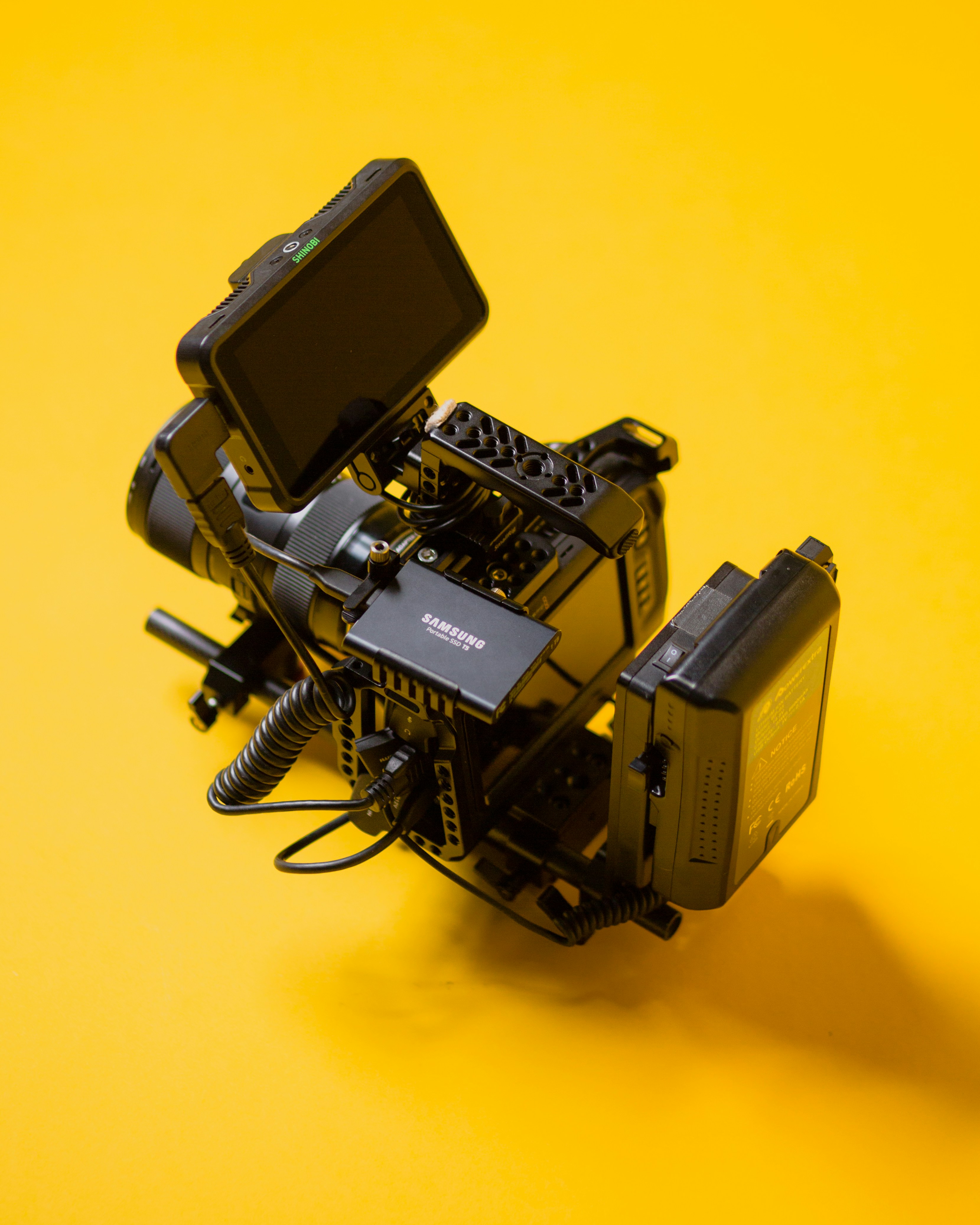 A professional camera rig showcasing an array of monitors and accessories against a vibrant yellow backdrop.