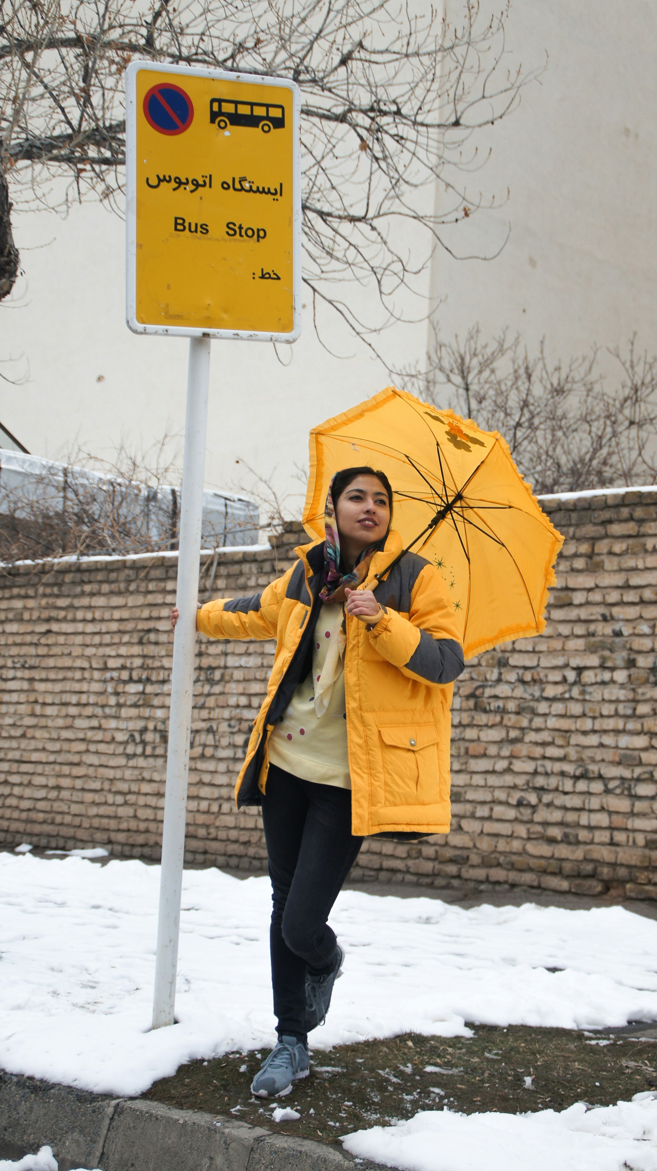 woman in yellow coat holding yellow umbrella