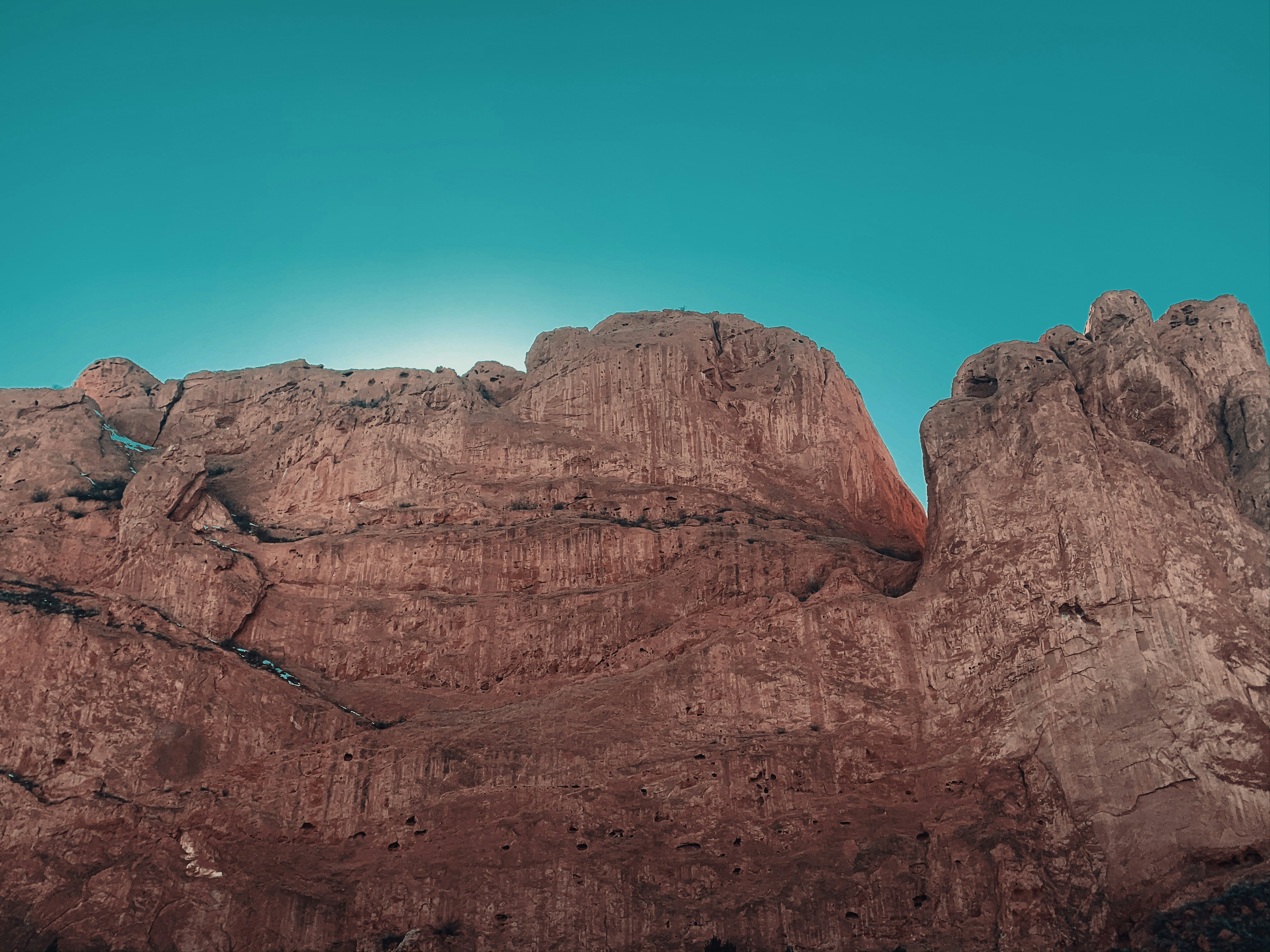 Rocky cliffs illuminated by sunlight against a vivid cyan sky.