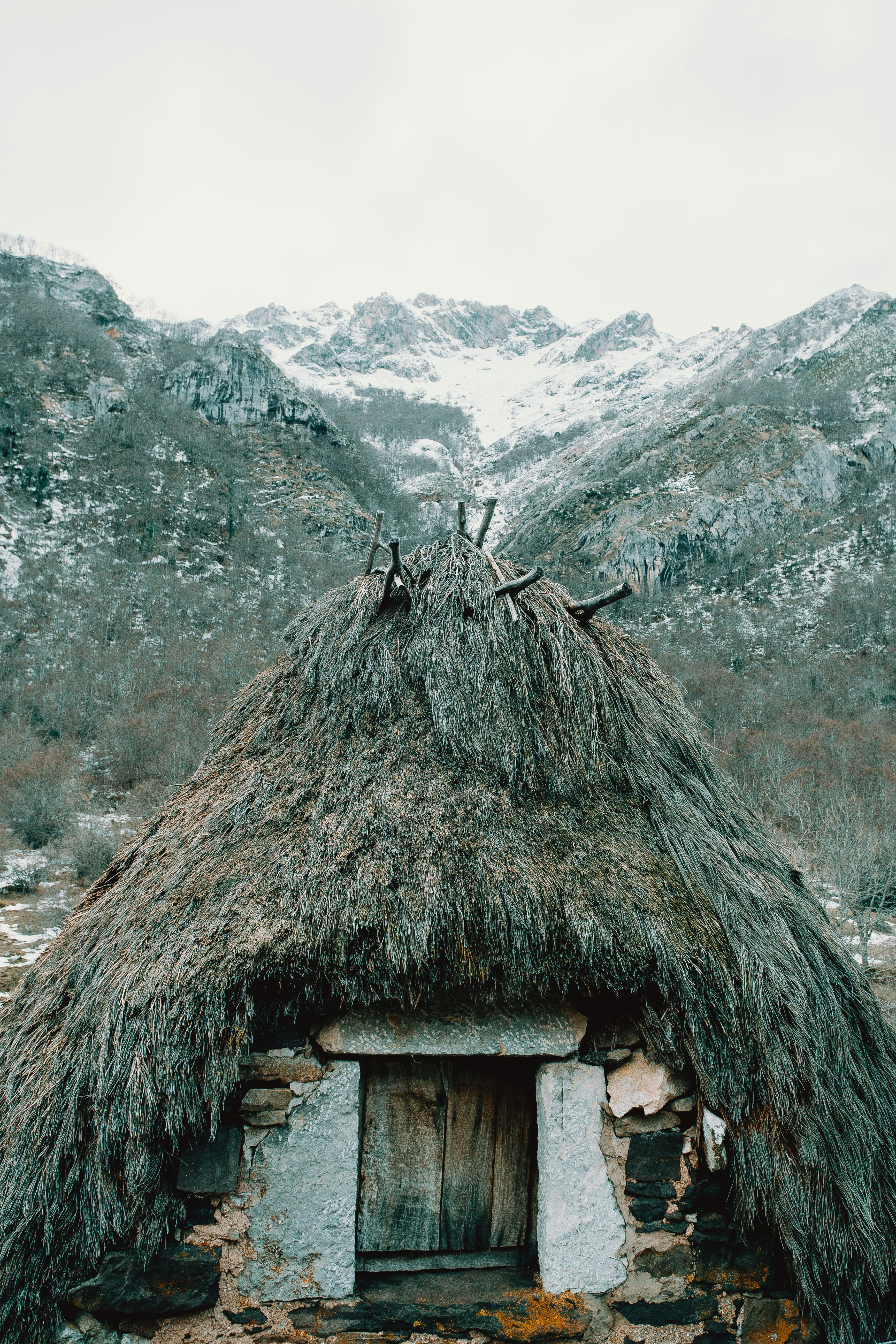 brown wooden house near snow covered mountain during daytime
